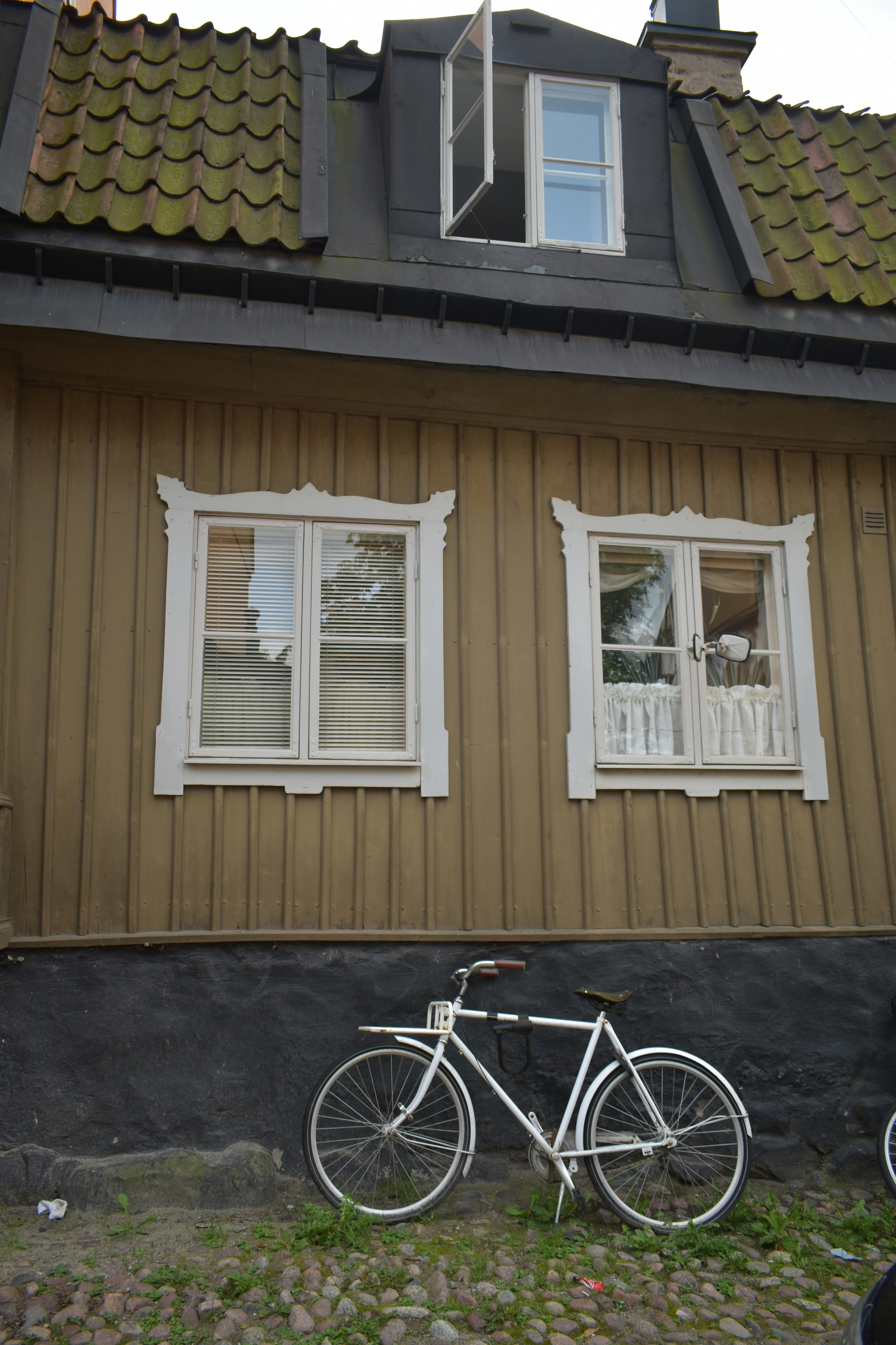 White Bicycle Resting Against a Timbered Facade Beneath a Dormer