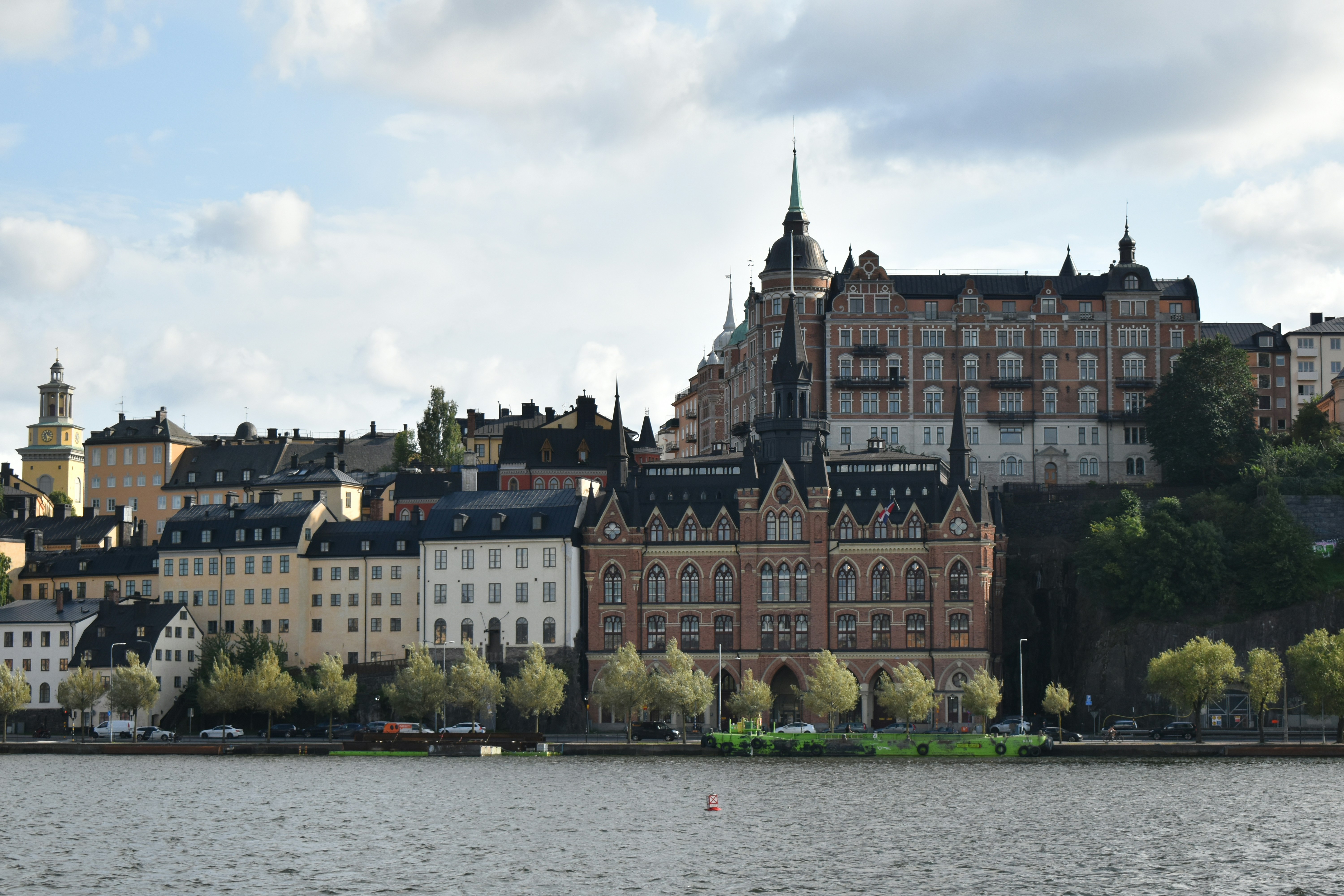 Ornate historic buildings line a waterfront under a partly cloudy sky.