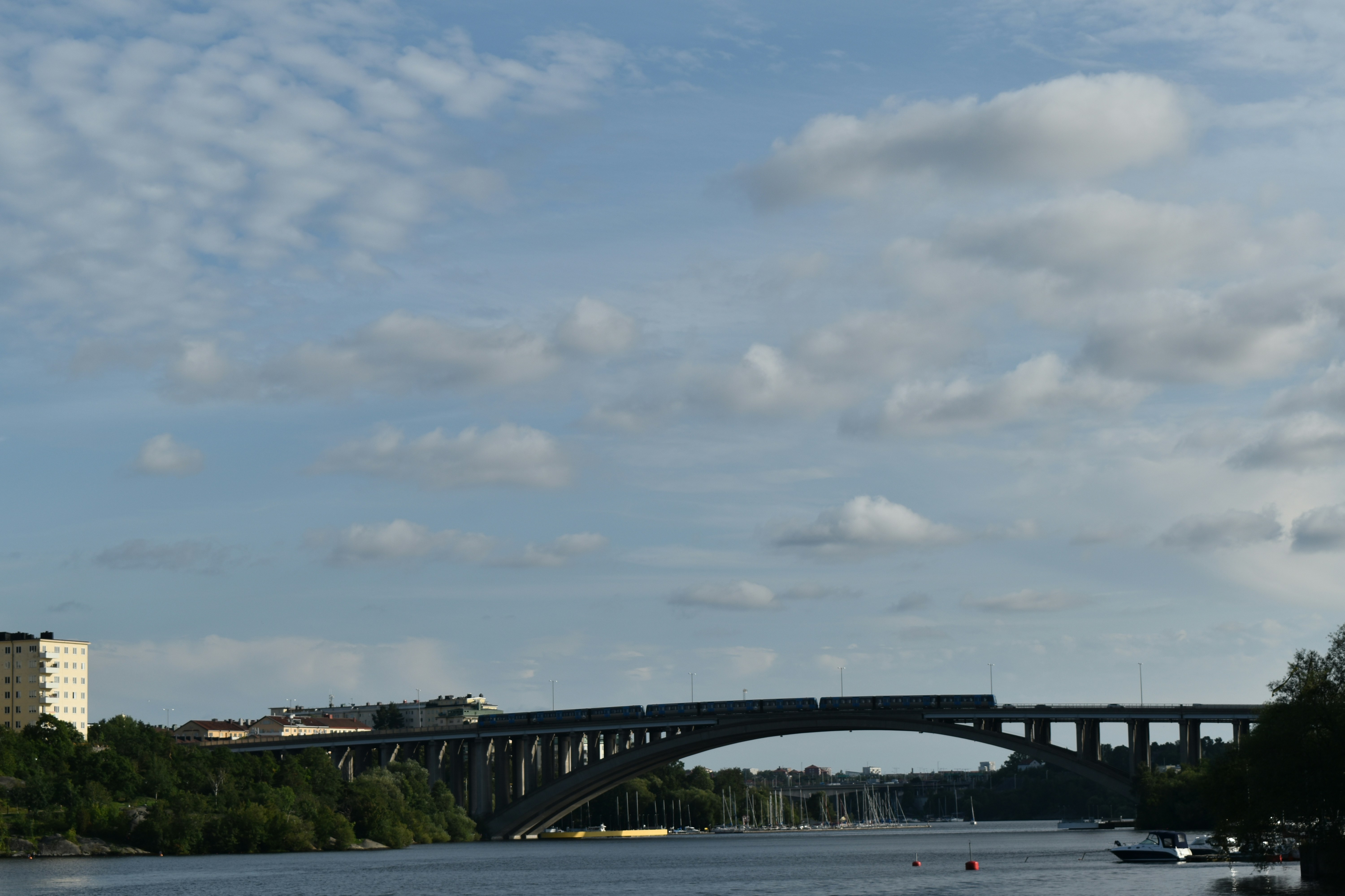 Bridge arches gracefully over a calm river under a sky dotted with fluffy clouds.