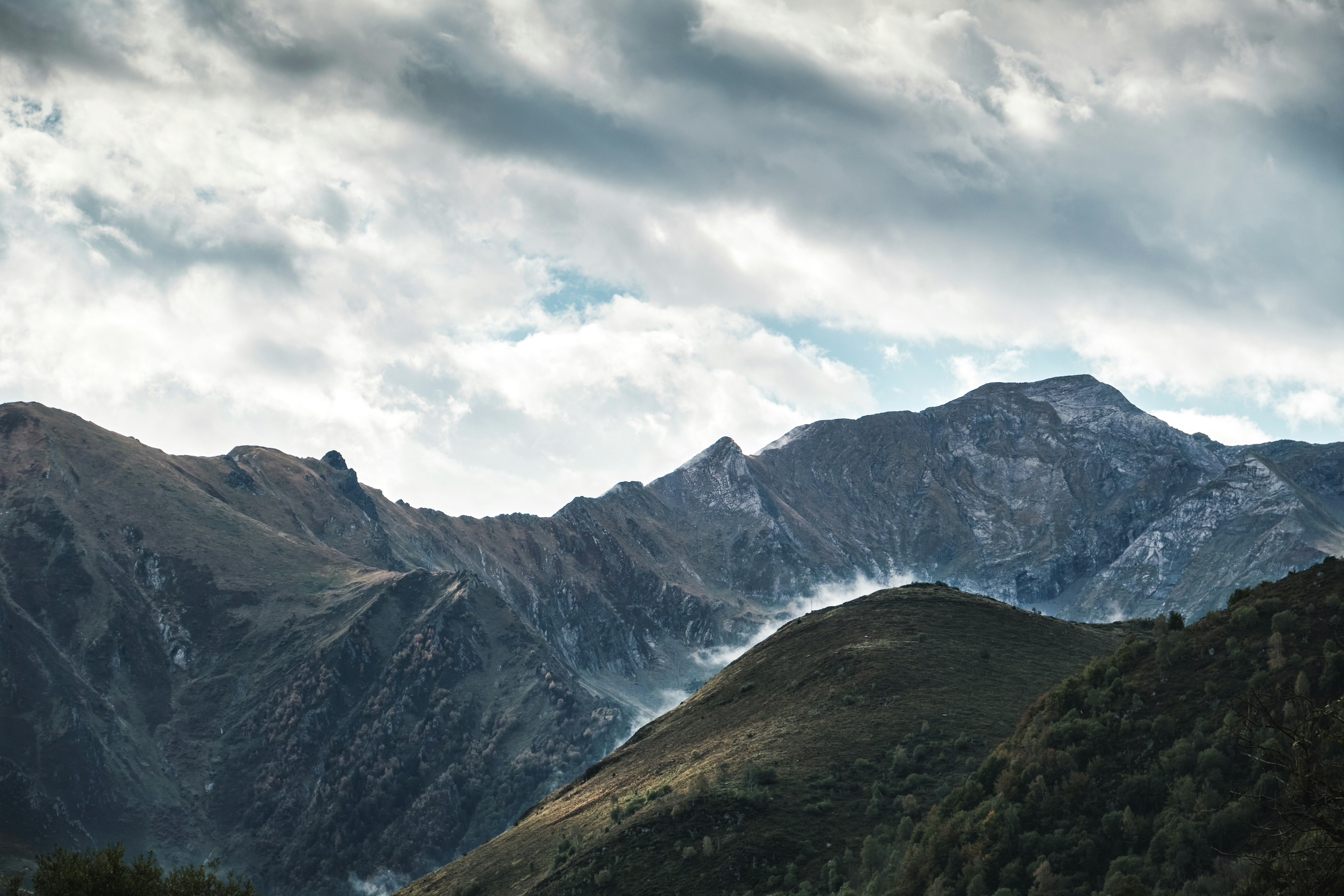 Clouds drift over rugged mountain ridges in the Pyrenees, creating a dramatic landscape.