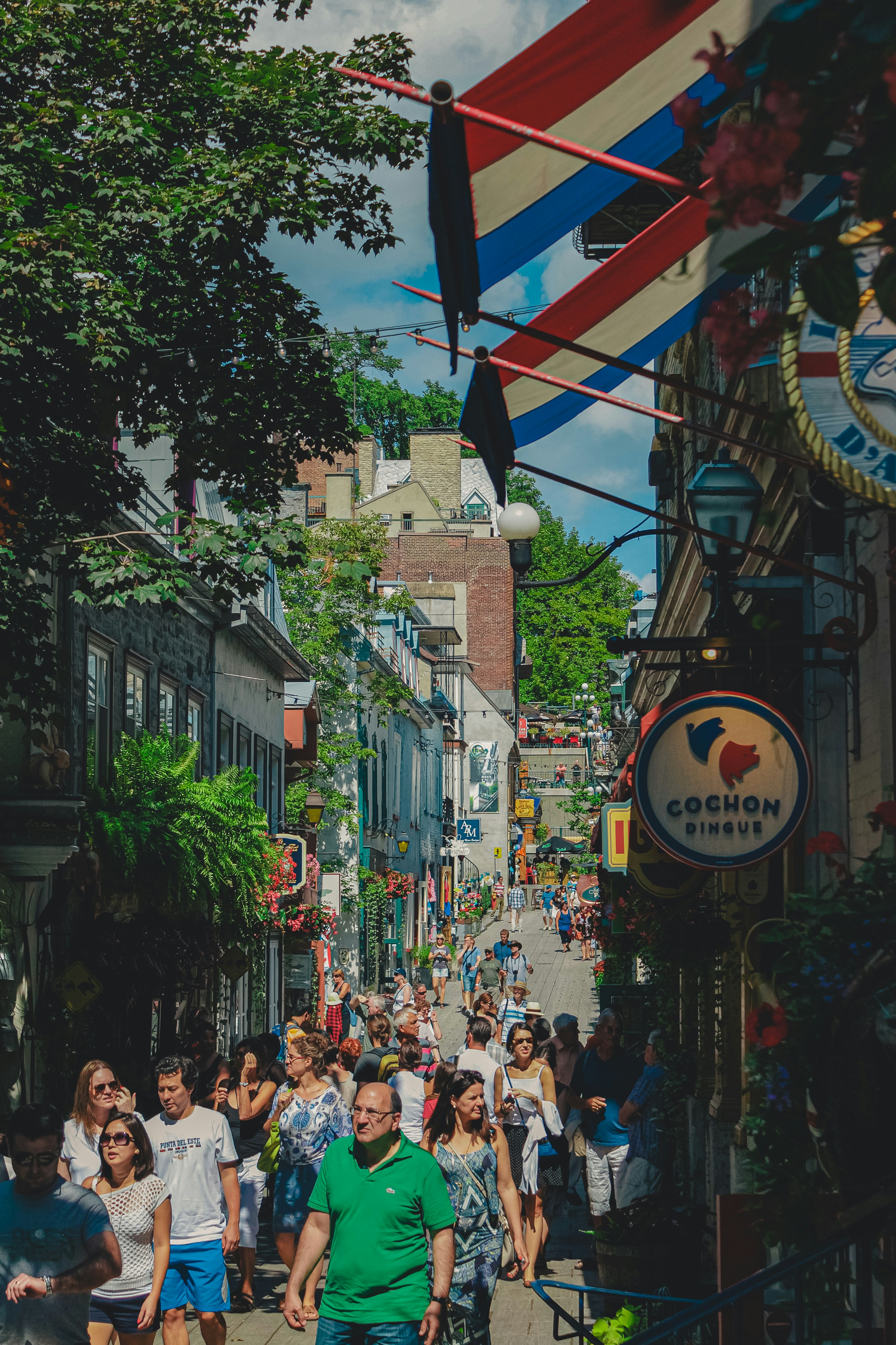 A crowded street scene with flags overhead. photo – Free Woman Image on ...