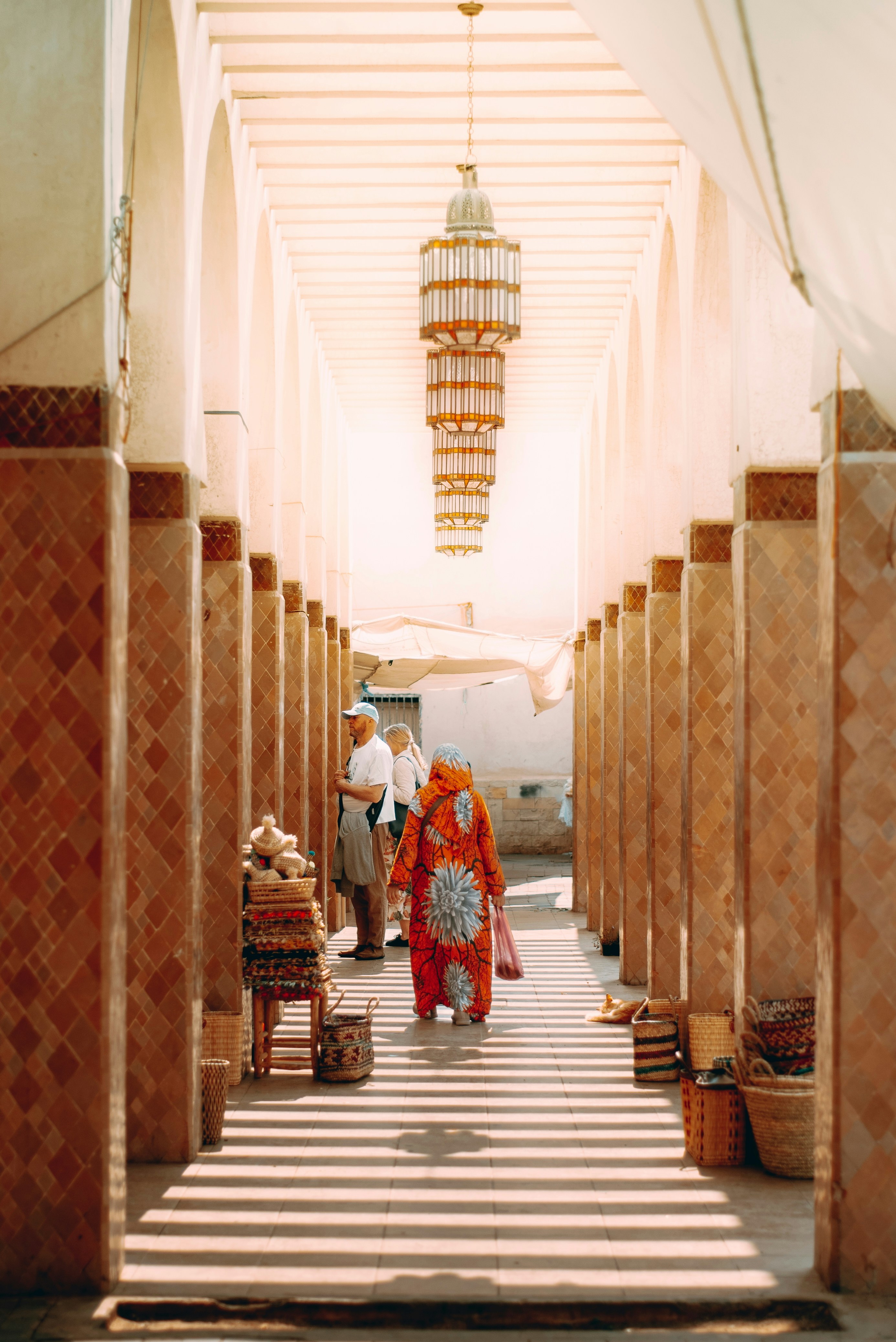 Amber Hallway Reverie: Red-Garbed Traveler in a Sunlit Colonnade