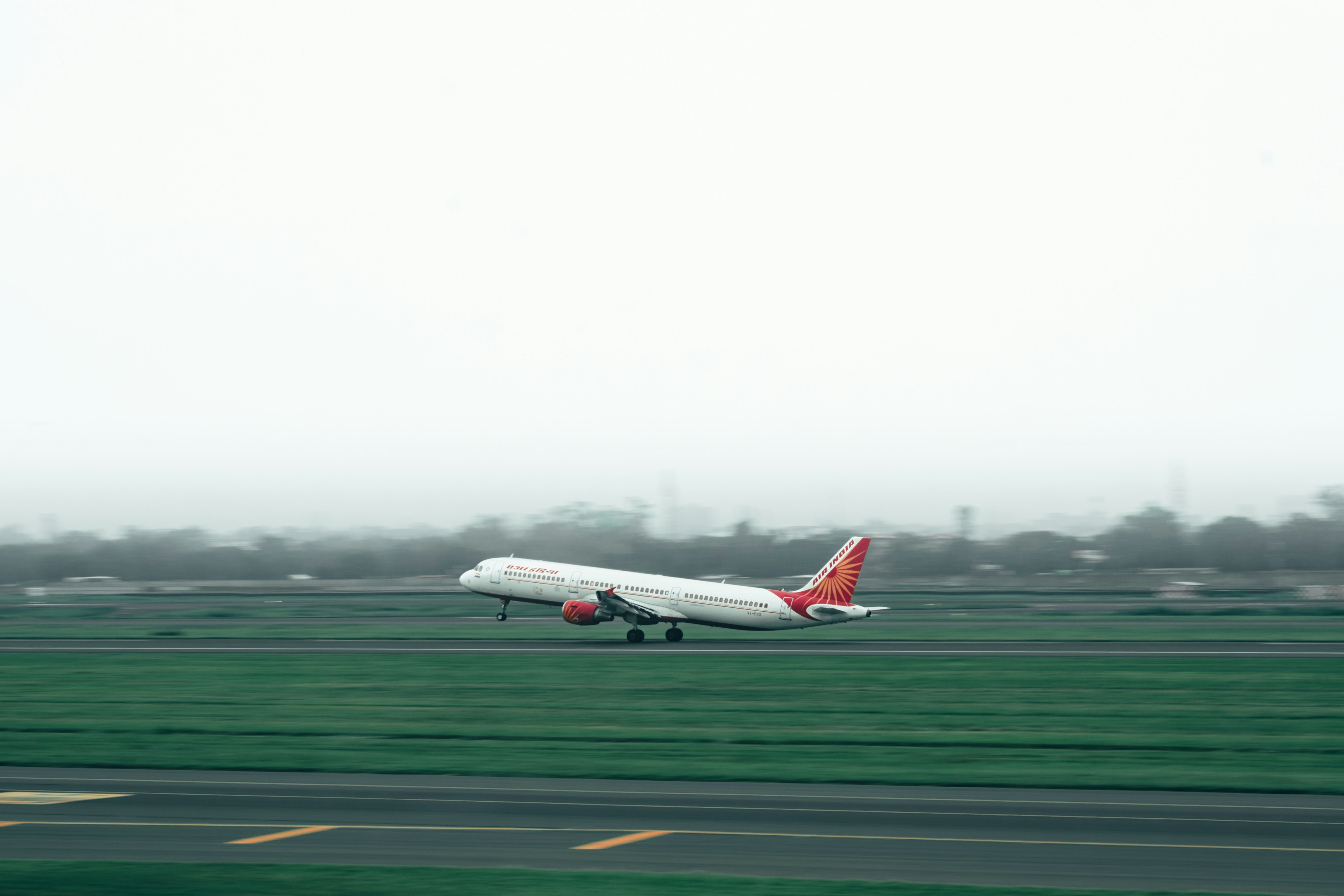 Passenger airplane taking off from a runway against a foggy skyline.