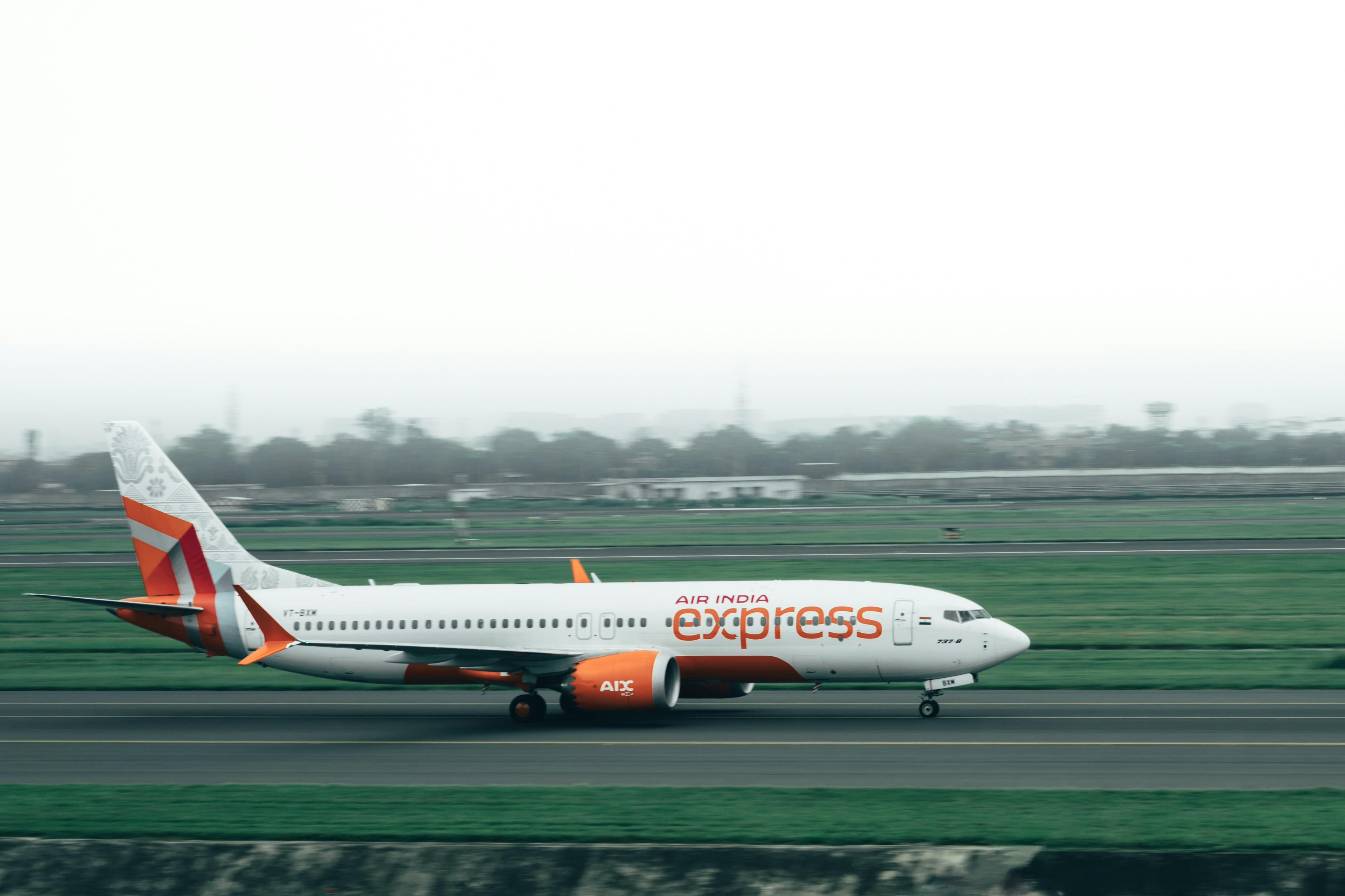 Passenger airplane taxis on a runway with overcast skies in the background.