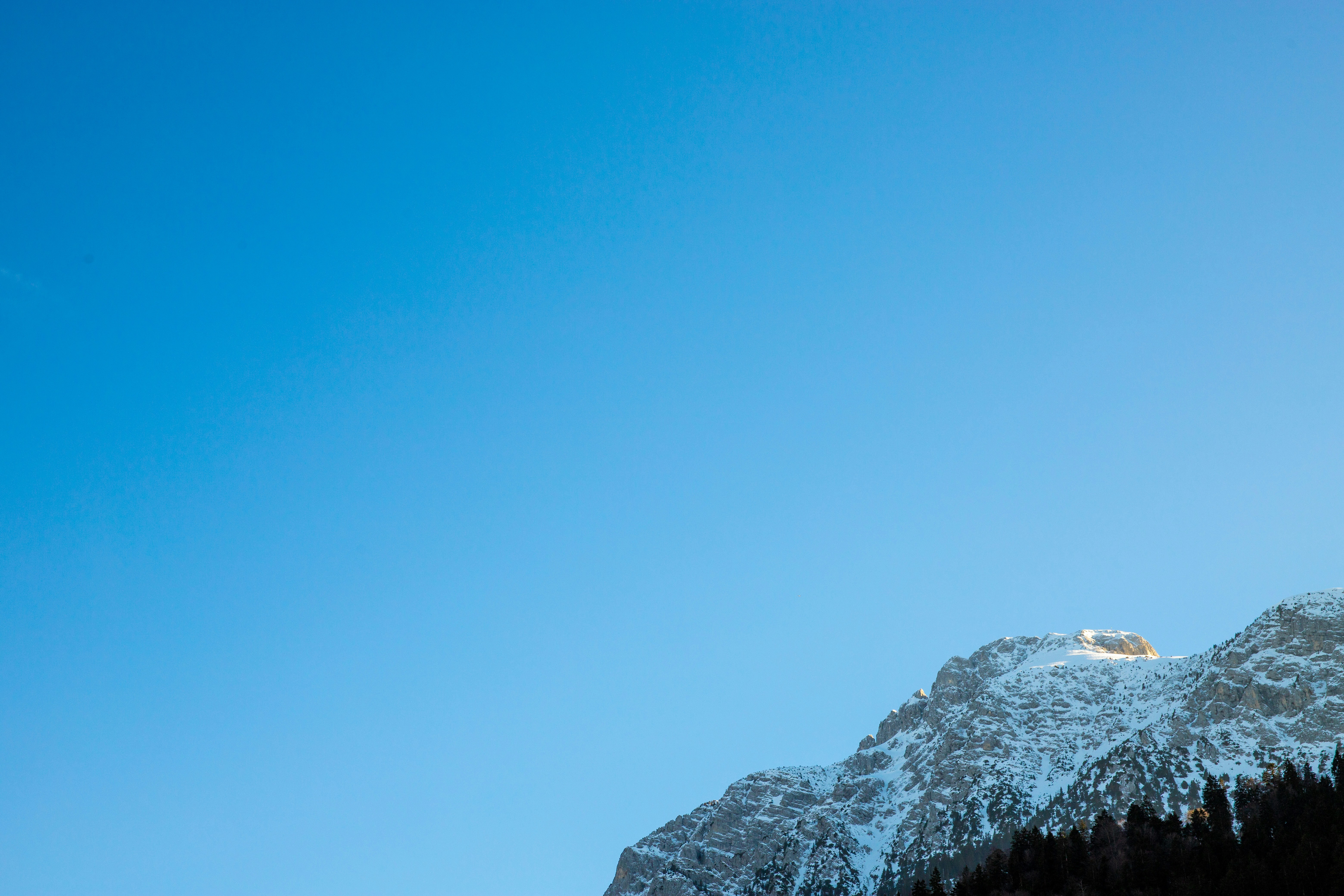 Snowy mountain peak beneath a vast blue sky.
