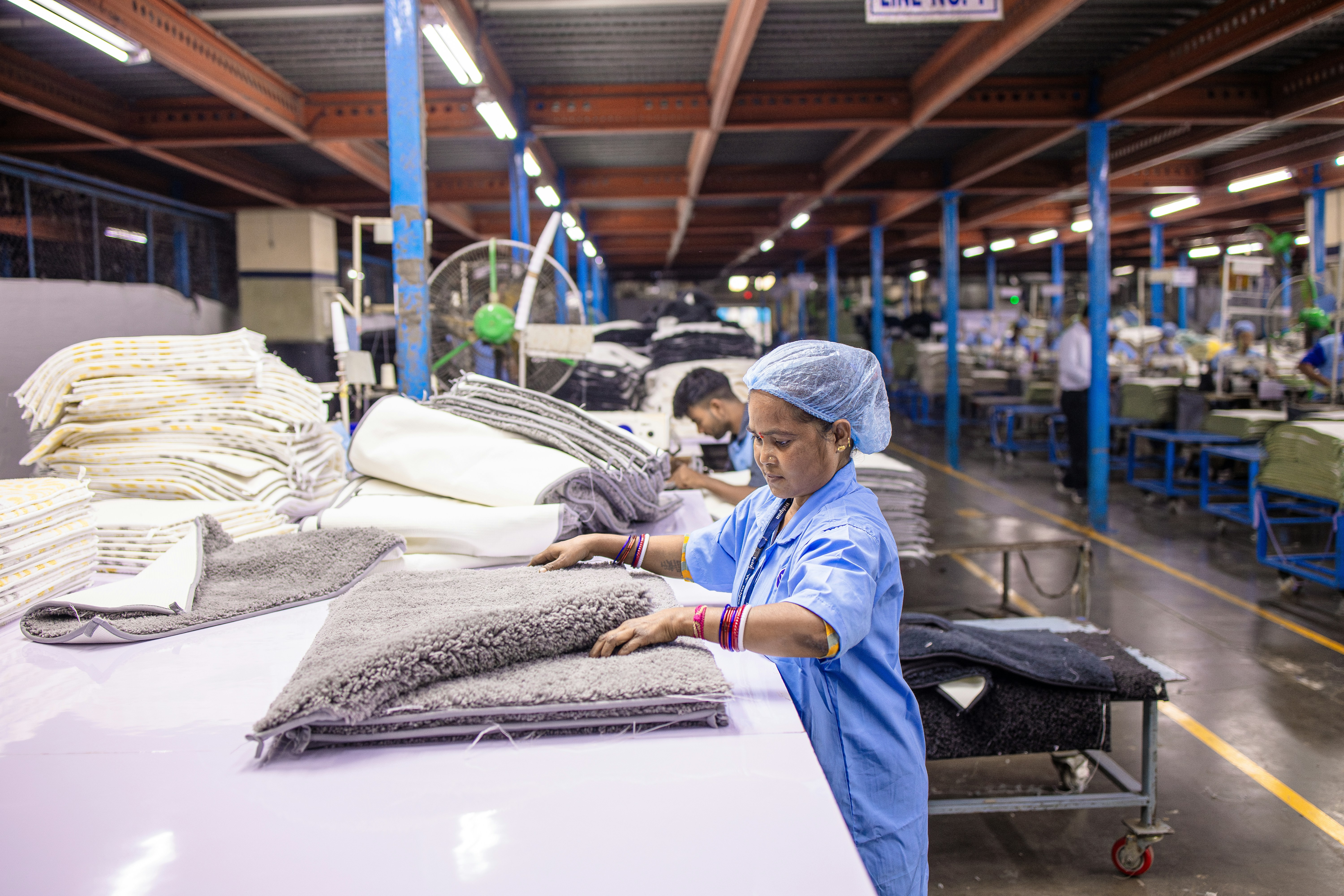 Workers are seen assembling textiles in a factory. photo – Free Human ...