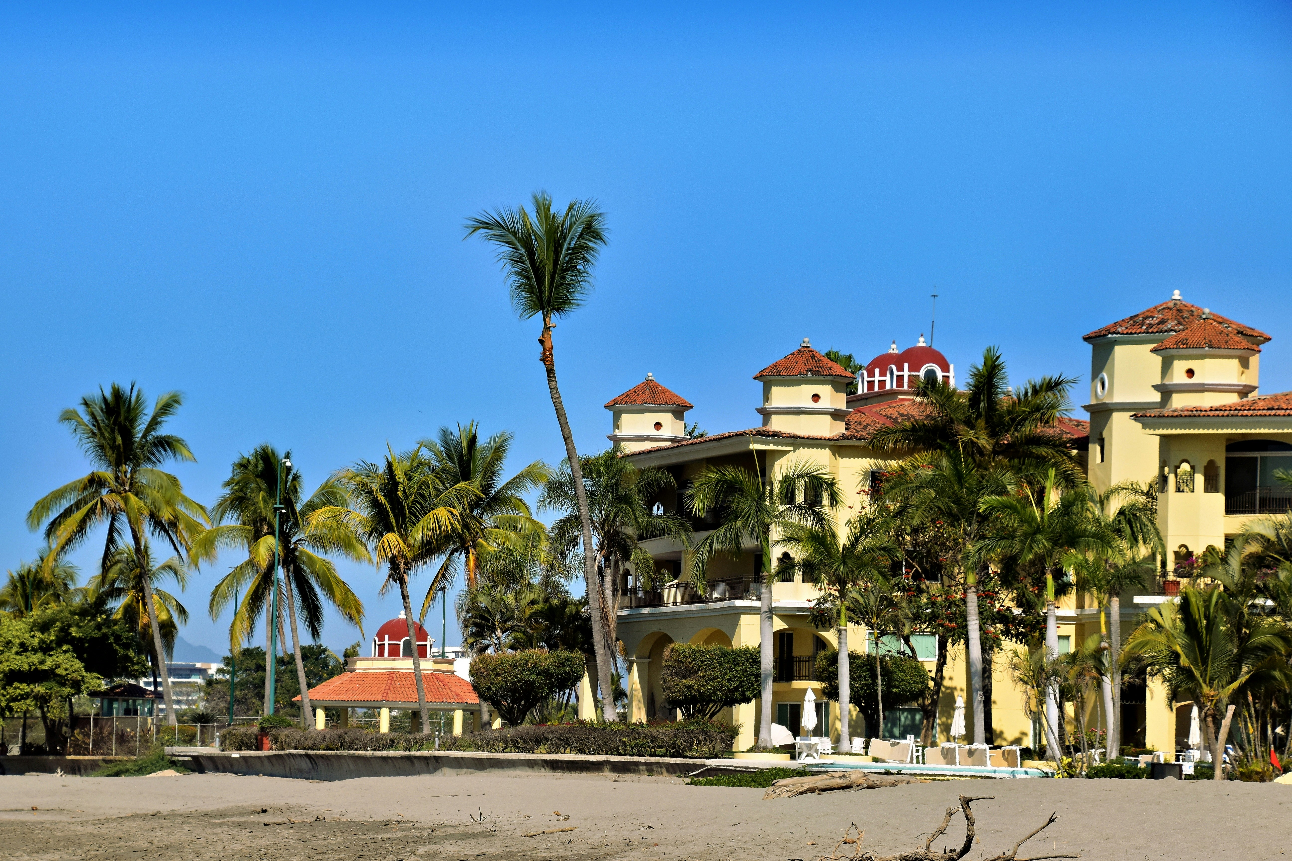 Elegant Mediterranean-style villa surrounded by palm trees under a clear blue sky.