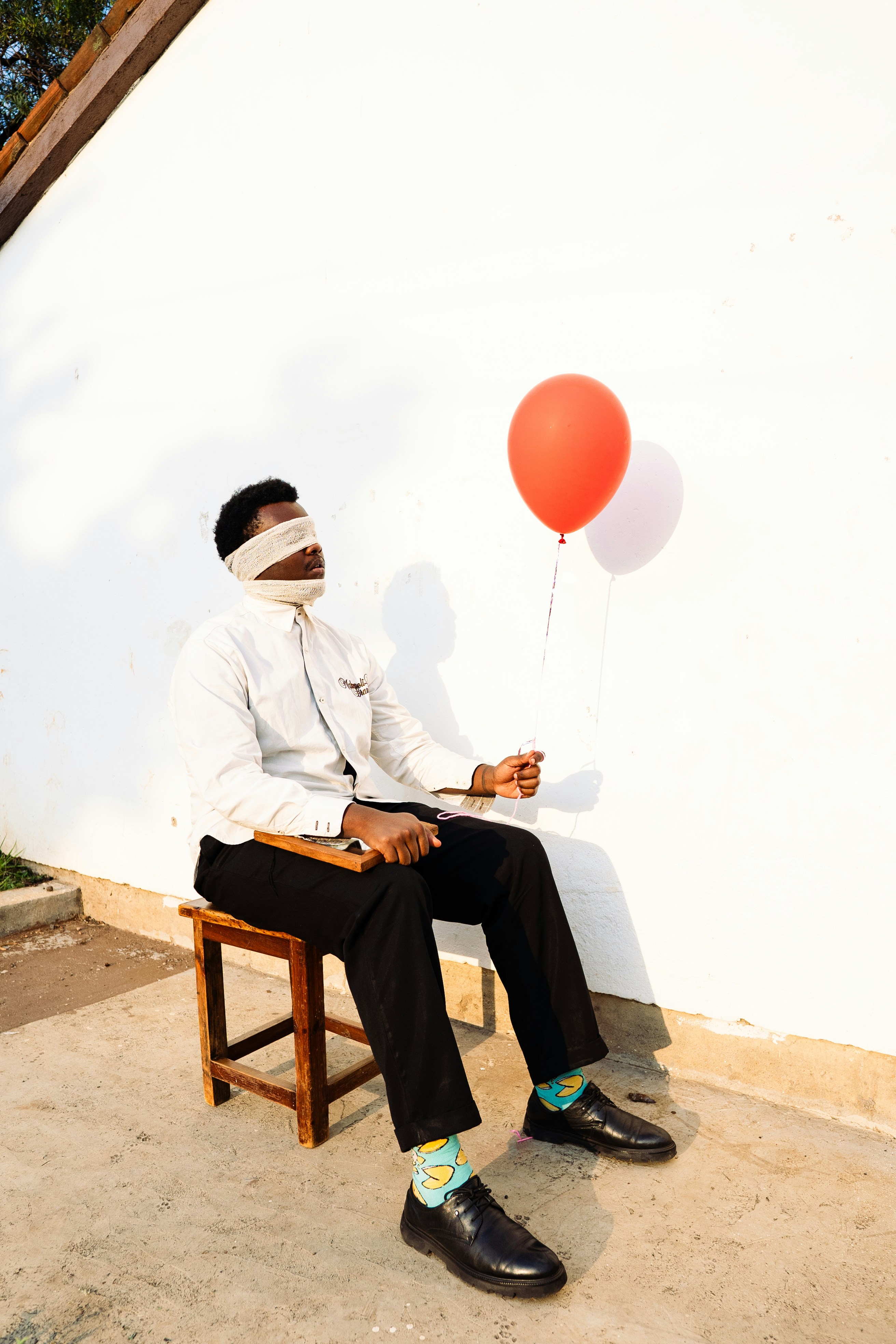Blindfolded man with a balloon sitting on a stool. photo – Free Man ...