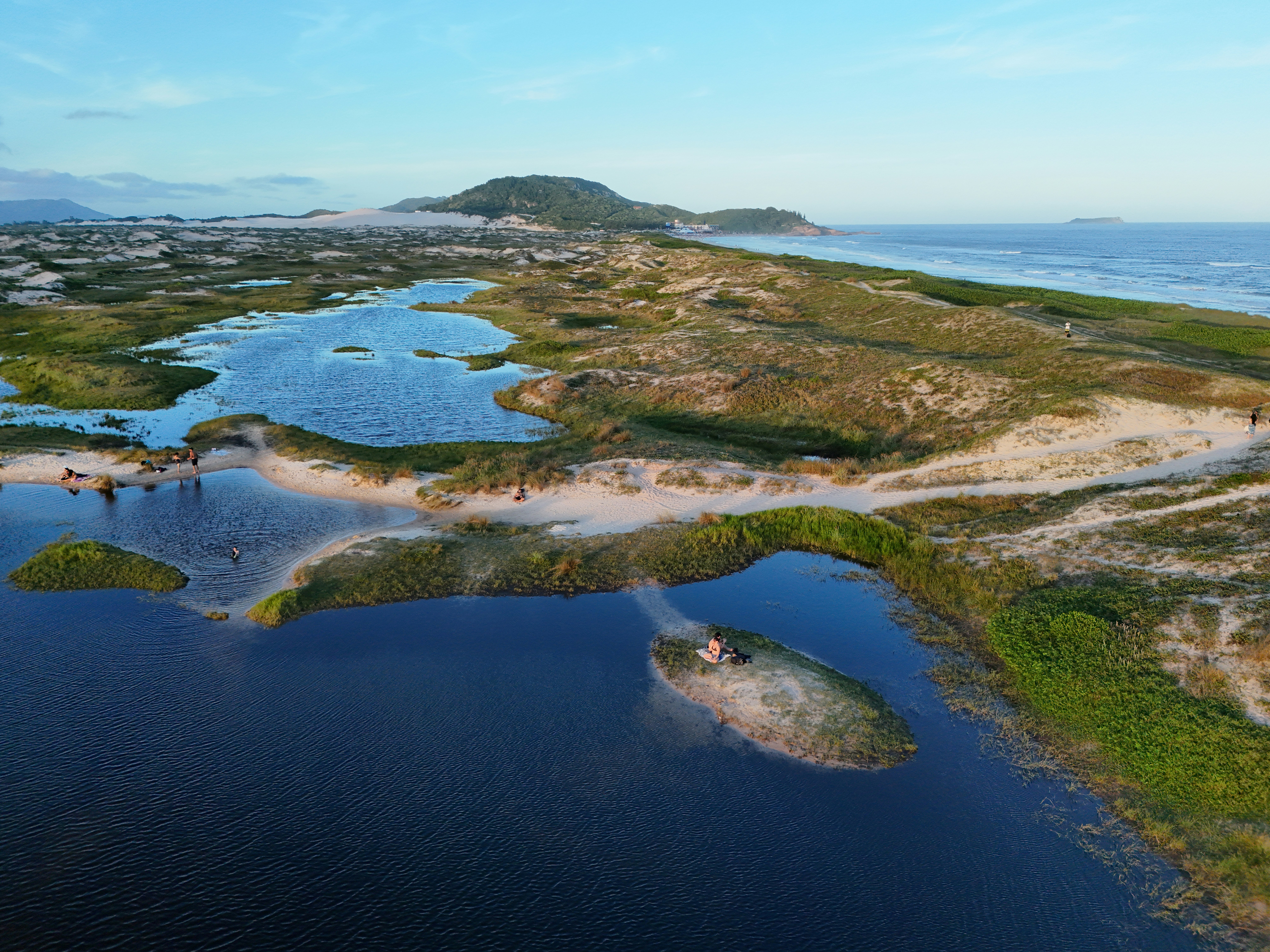 Aerial view of a tranquil coastal landscape with winding waterways and sandy dunes under a clear blue sky.