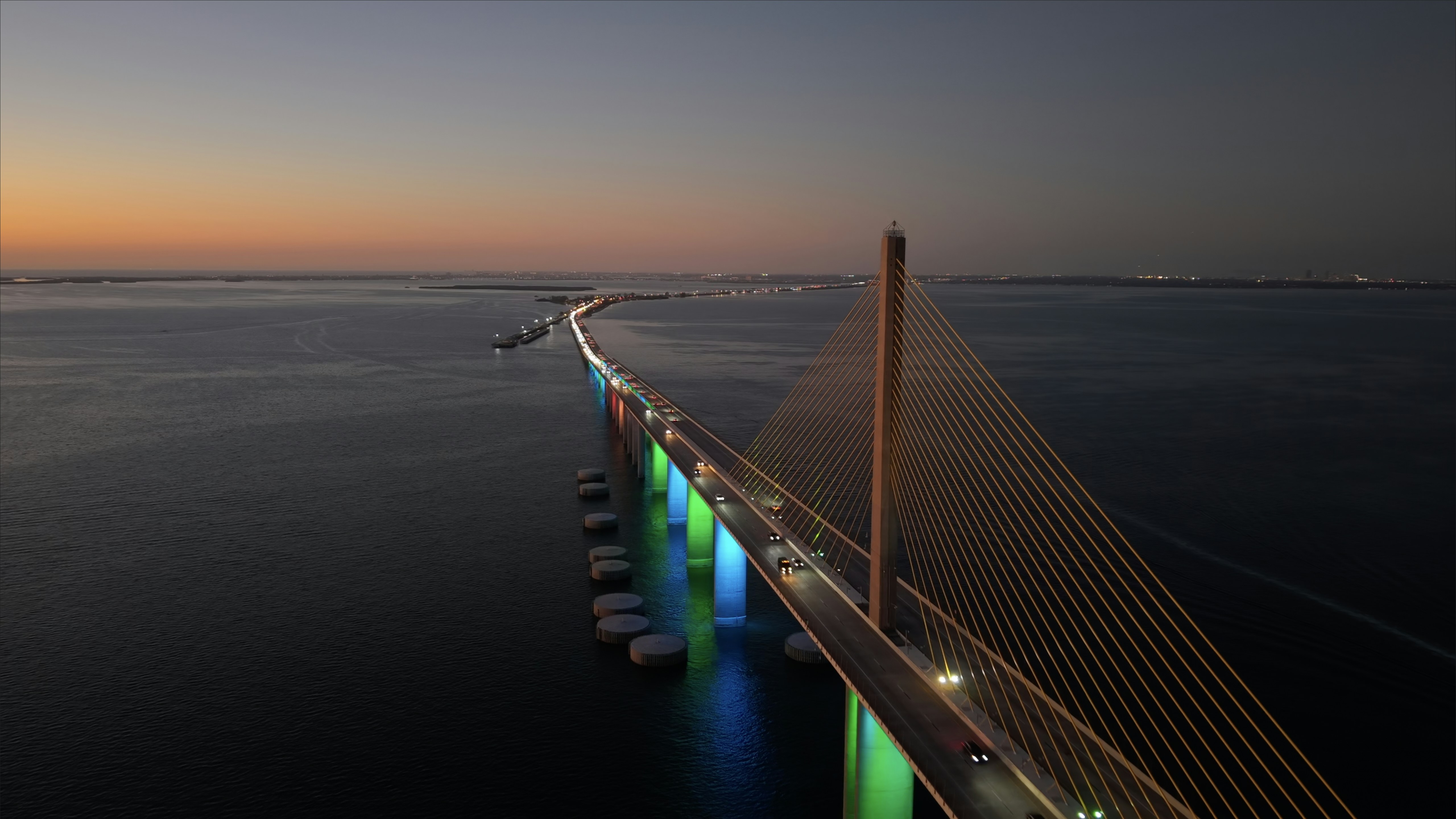 A lit-up bridge spans across water at dusk. photo – Free Travel Image ...