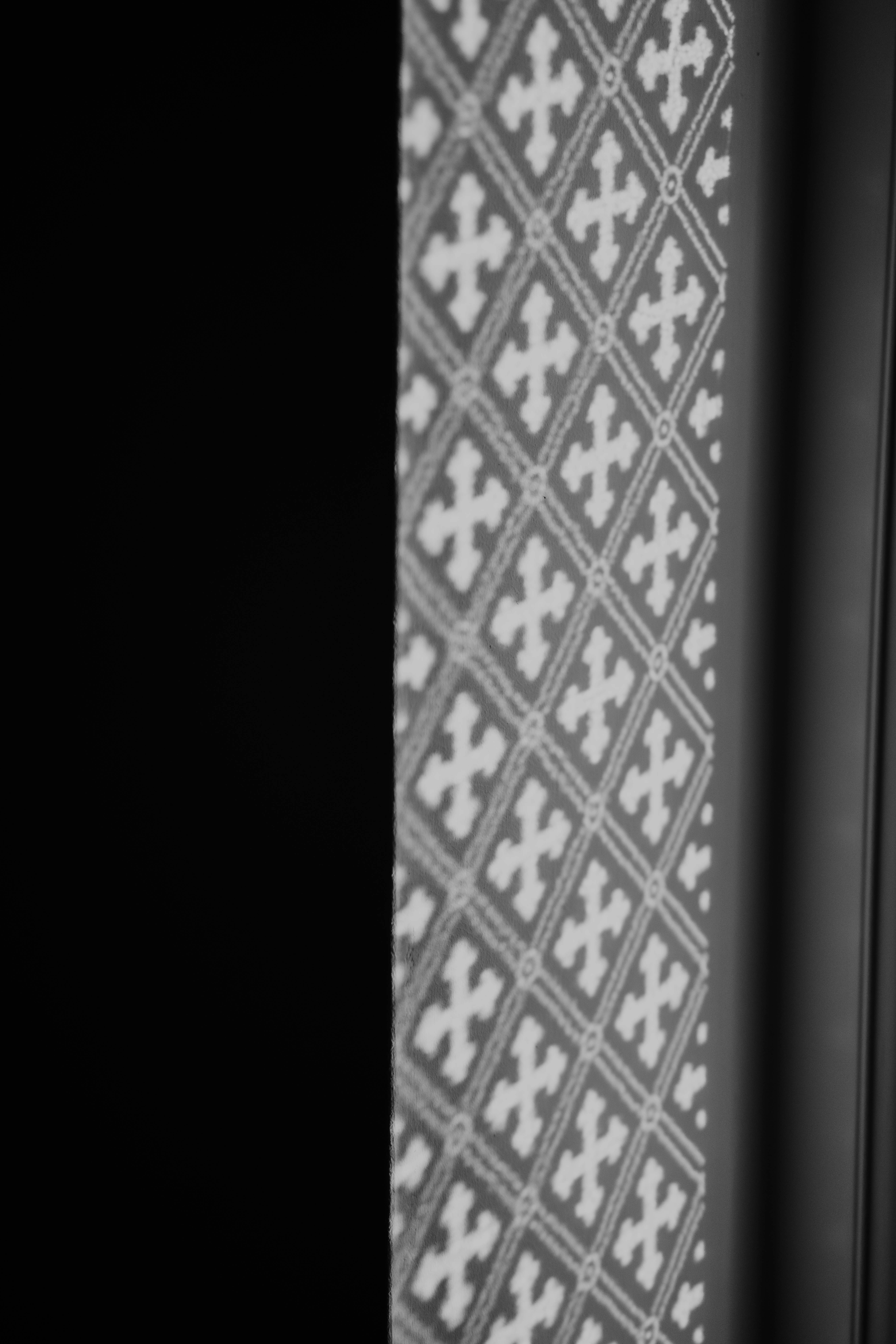 Intricate patterned fabric framed against a dark background, showcasing a blend of geometric shapes and textures.
