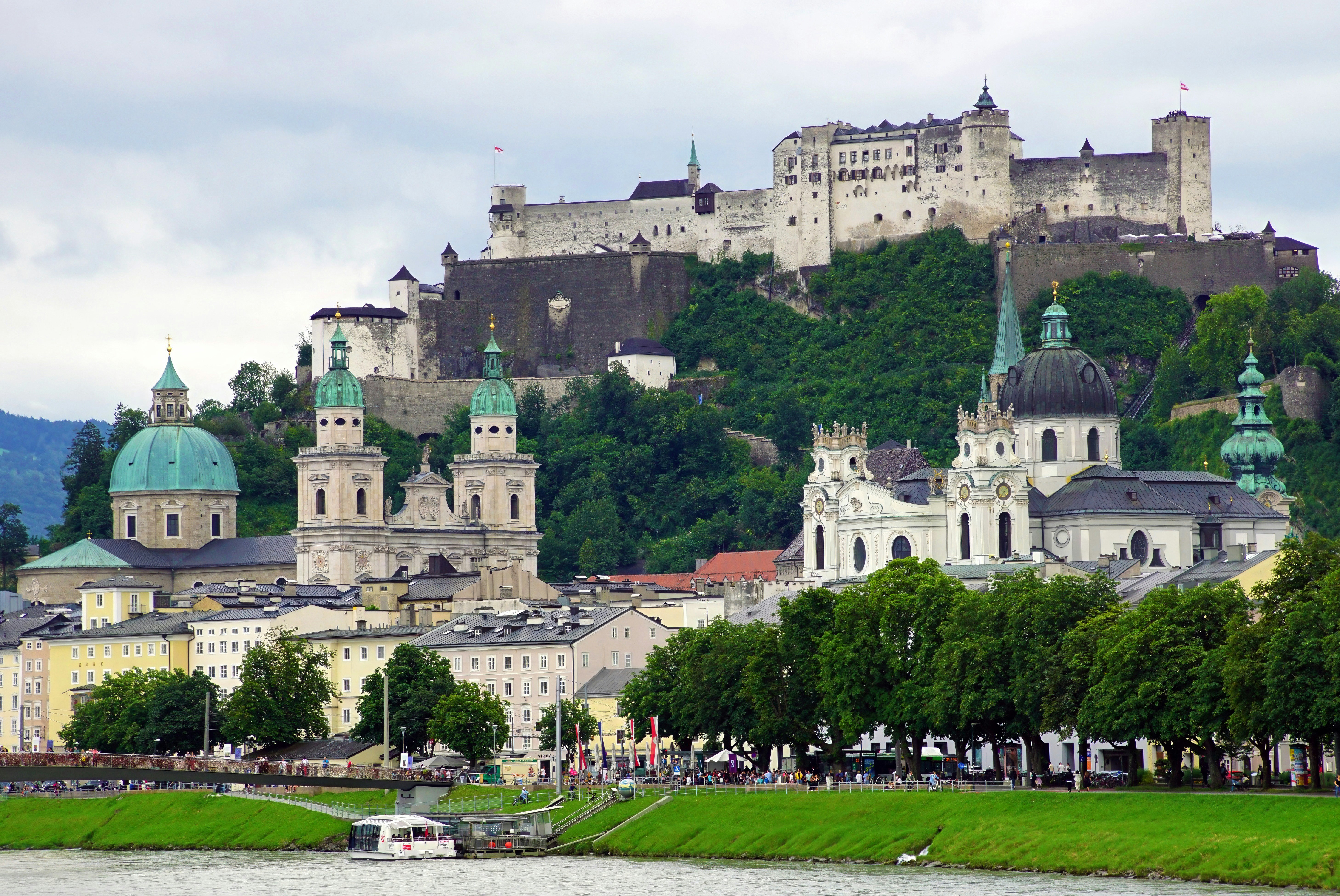 Salzburg overview with the old, large castle on the hill. | A cityscape shows salzburg, austria, on a hill.