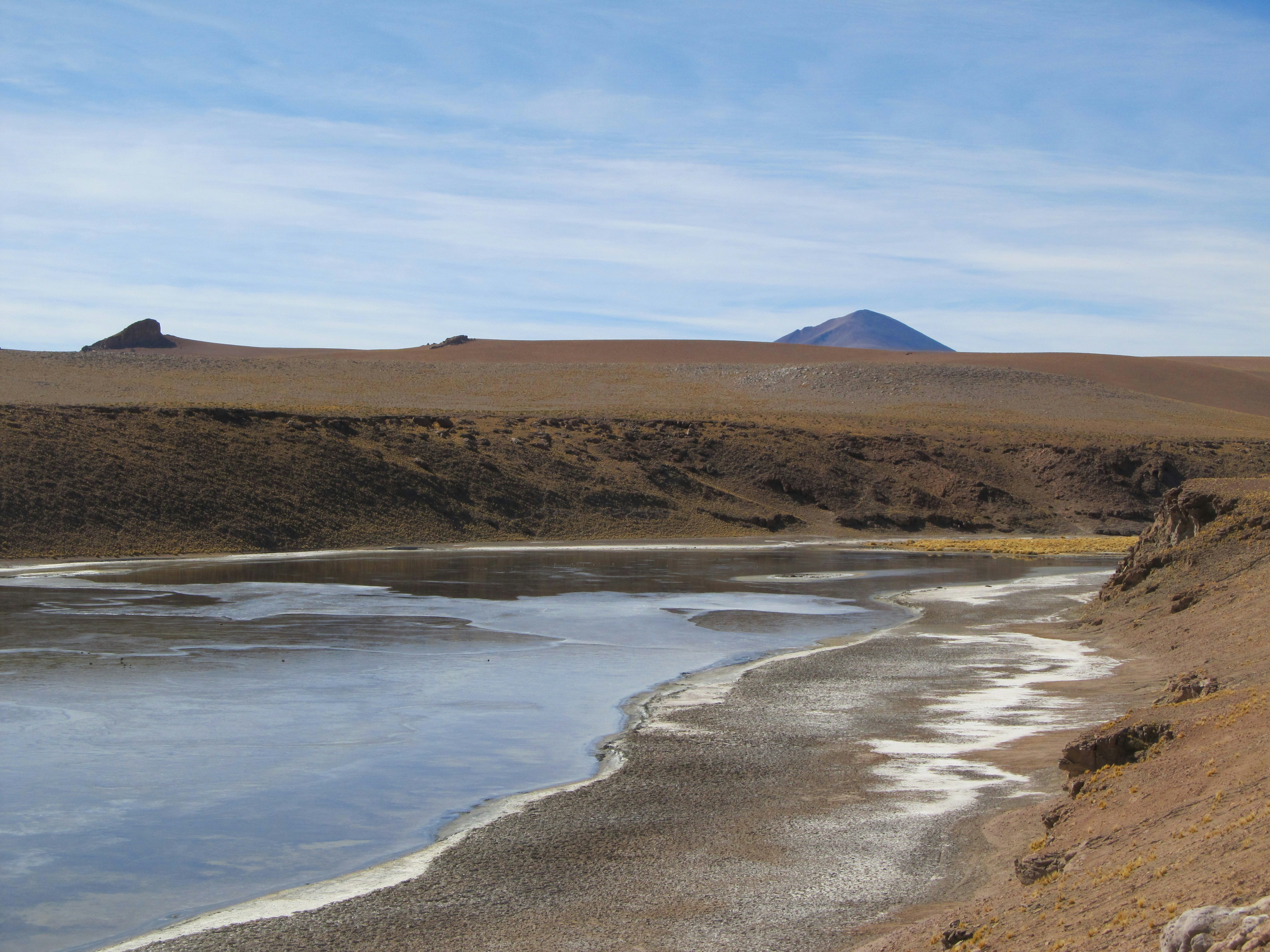 Vast desert landscape with a reflective water basin under a clear blue sky.