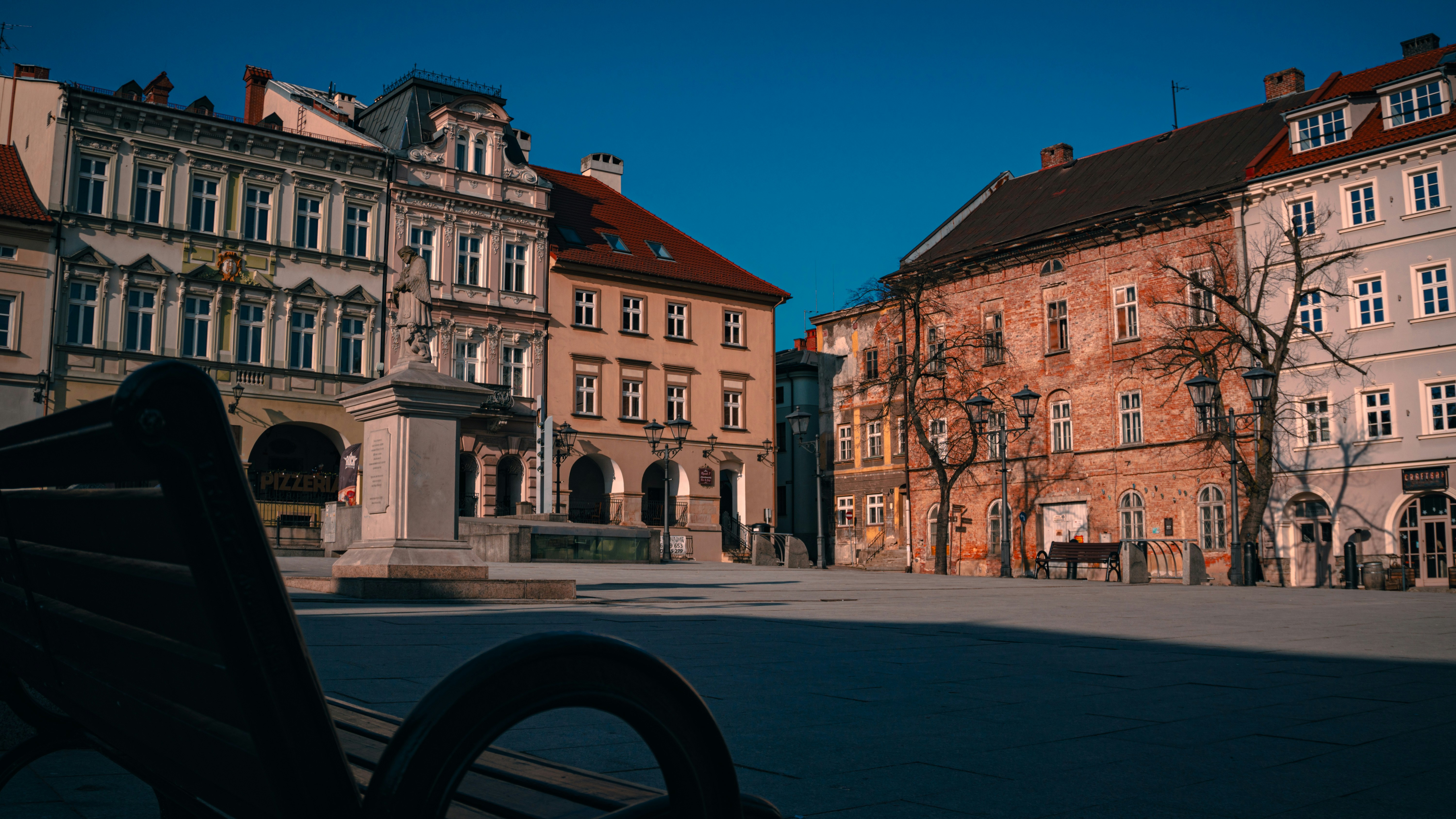 Historic buildings bathed in warm sunlight on a quiet city square.