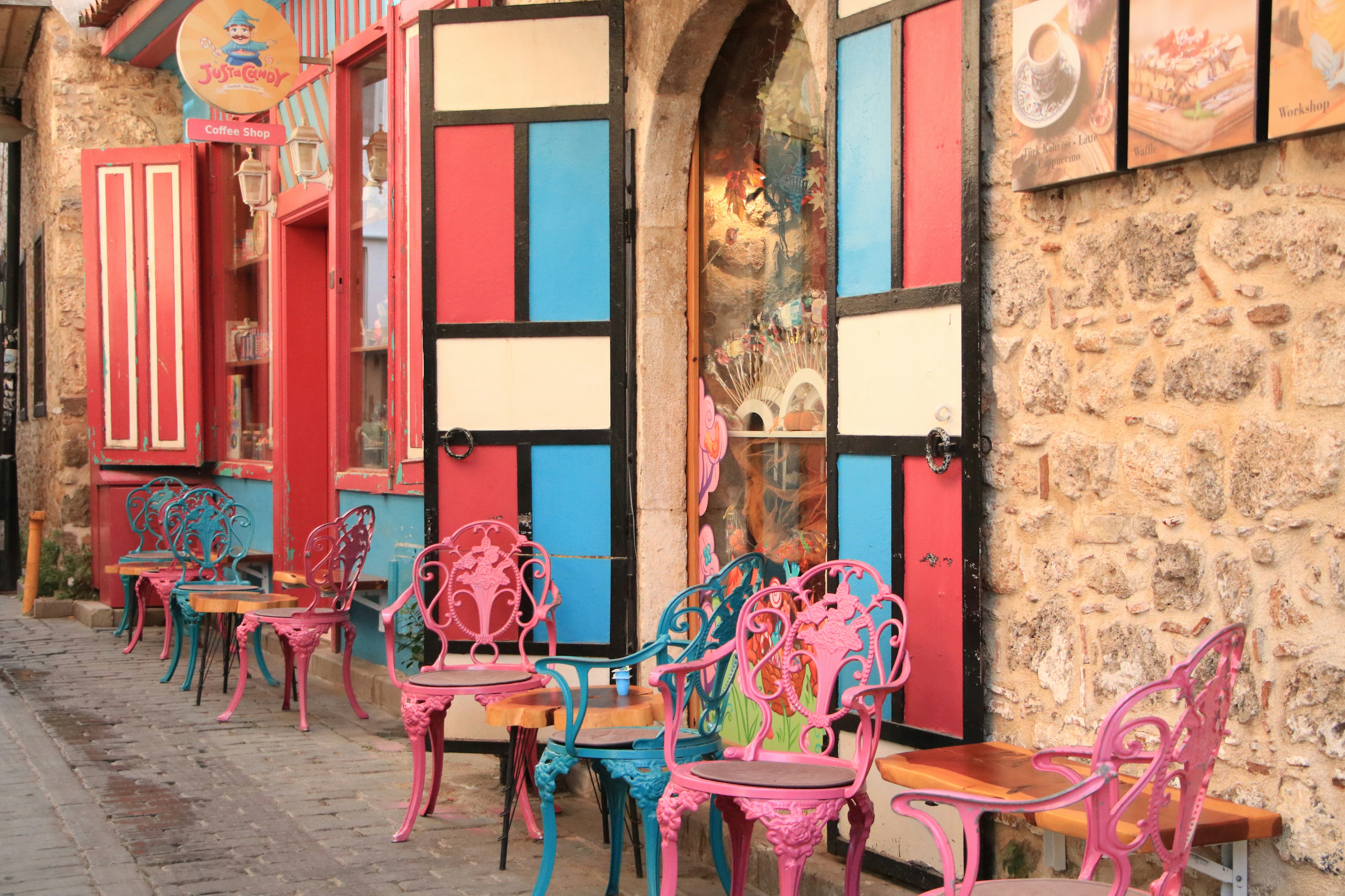 Colorful chairs and doors create a vibrant scene outside a quaint café in Kaleiçi, Antalya.