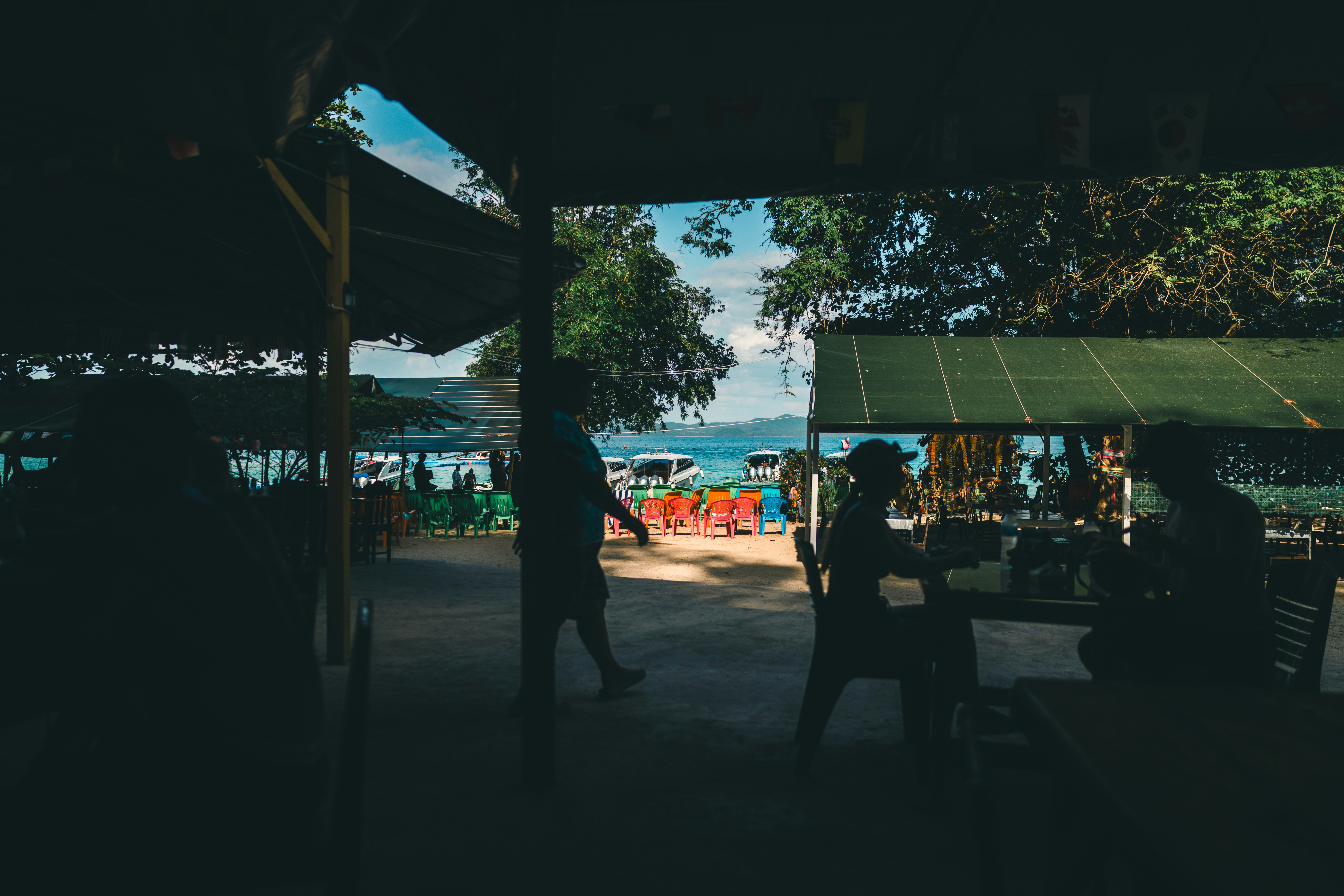As pessoas sentam e caminham perto de um café à beira-mar. foto ...