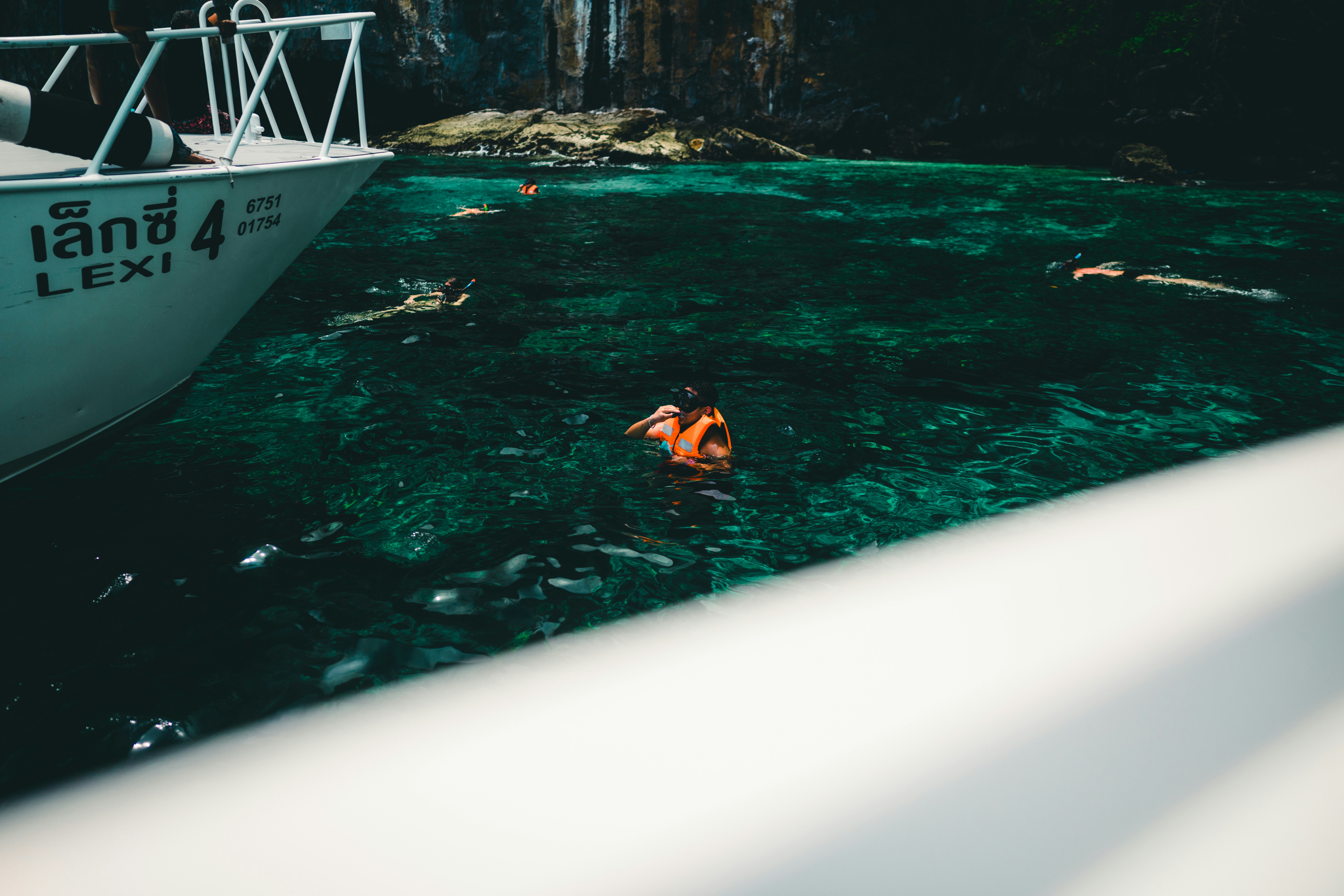 Emerald Cove: A Sole Swimmer Beside a Moored Vessel