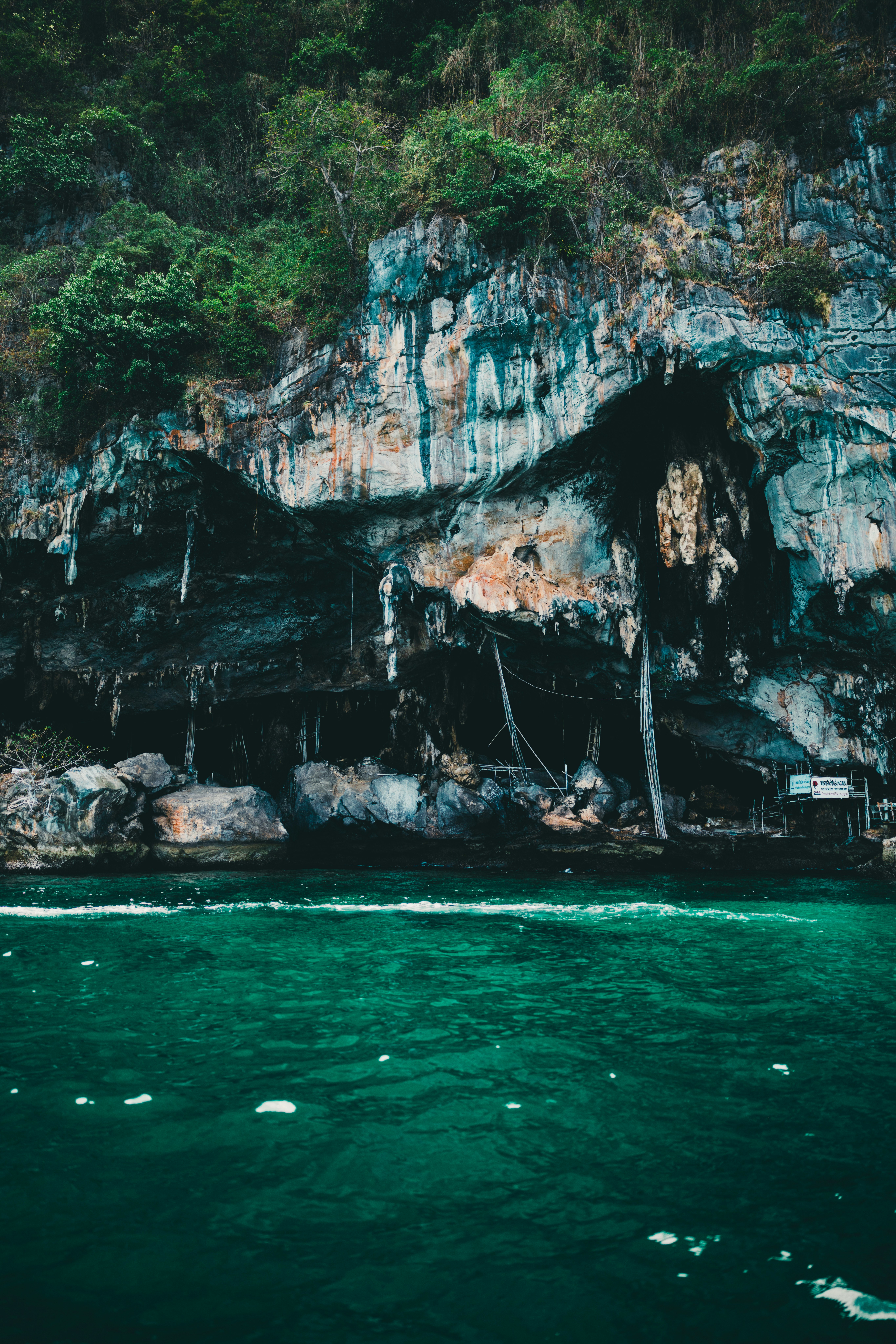 Cliffside caves overlook turquoise water and a small pier. photo – Free ...
