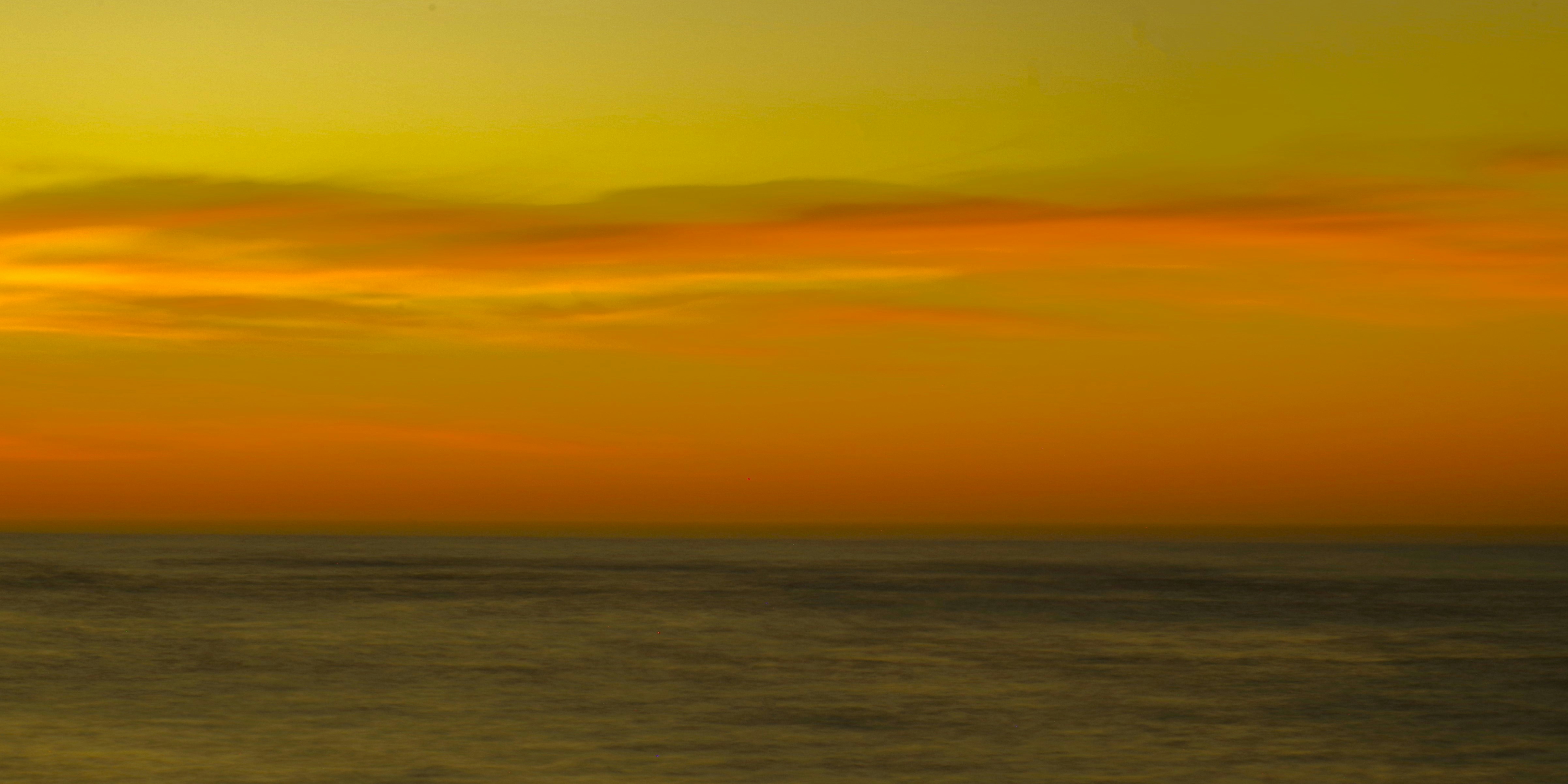 ICM technique blurs sunset hues over a calm ocean.