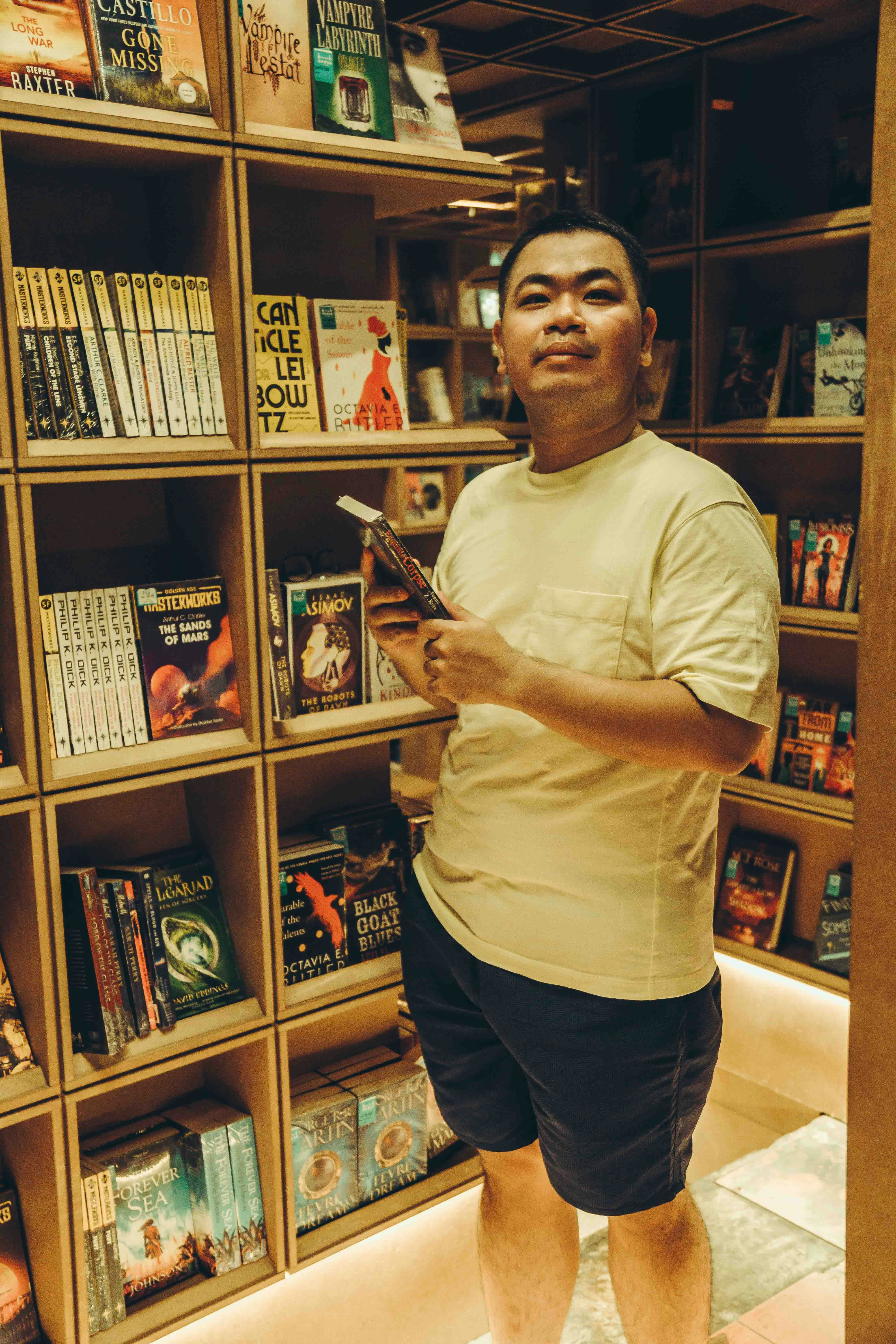 Individual browsing through a collection of books in a cozy bookstore setting, surrounded by shelves filled with various genres.