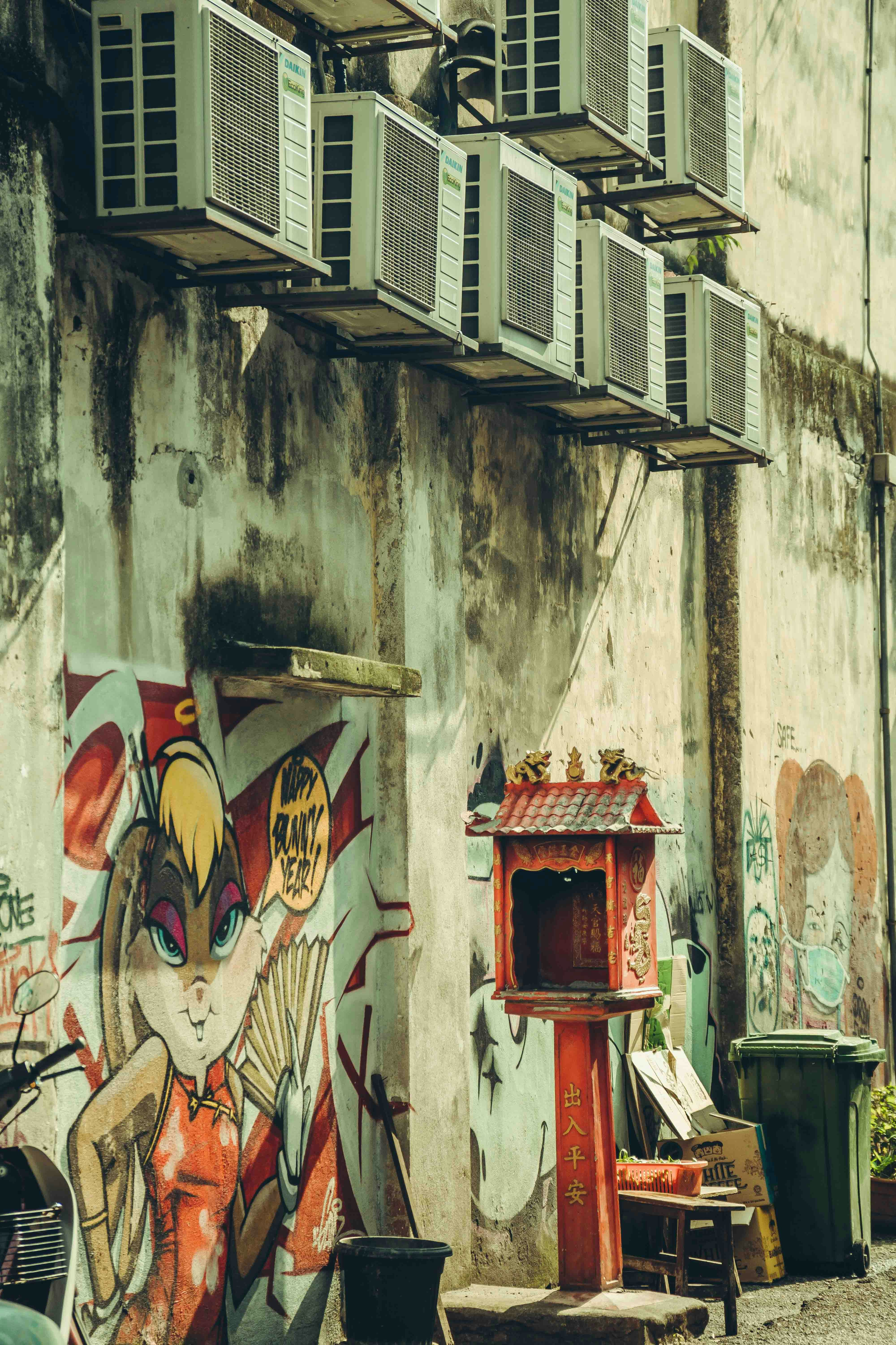 Red Shrine Beneath HVAC Giants in a Graffiti Alley