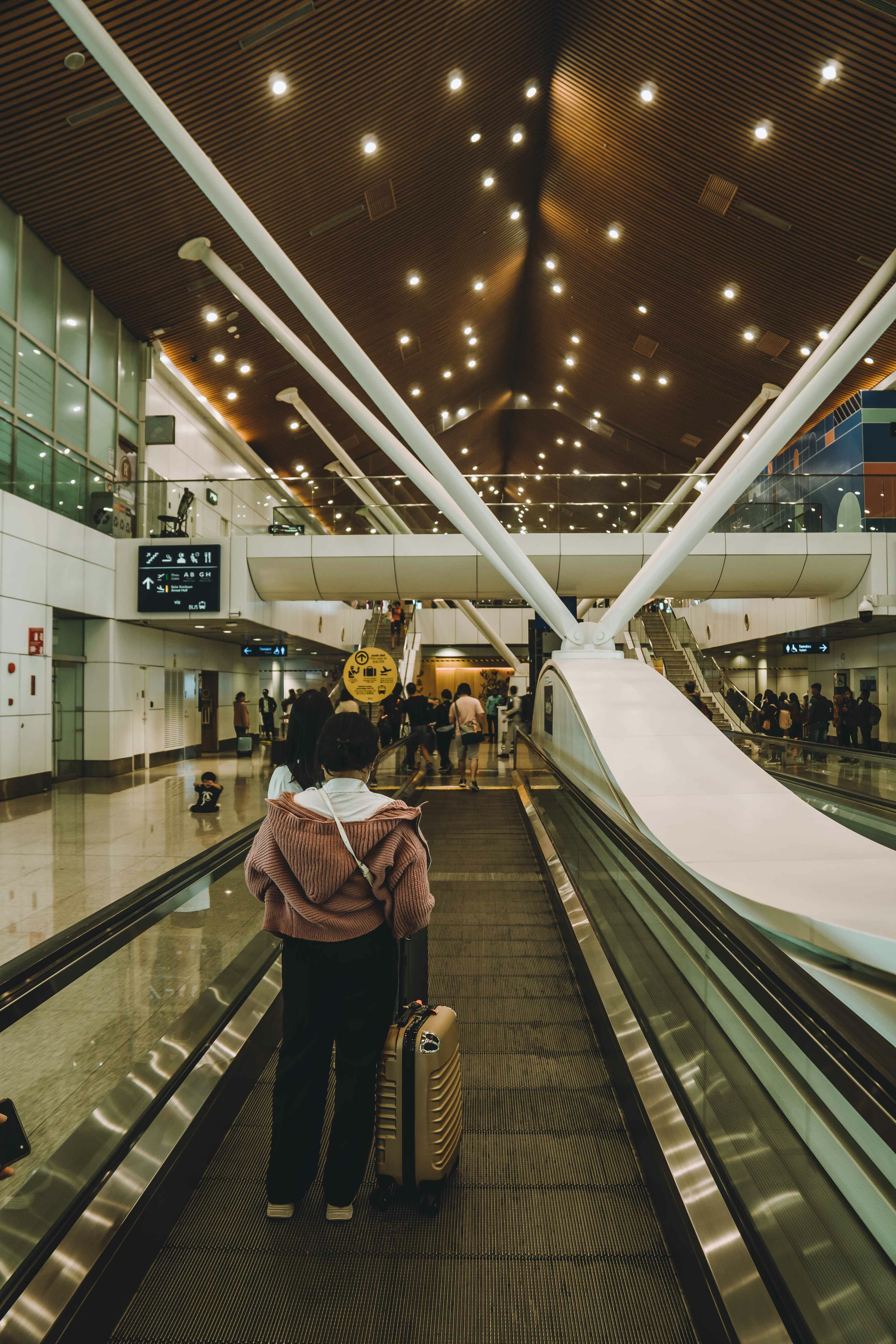 Traveler on the Moving Walkway Beneath a Cathedral of Light in a Busy Terminal