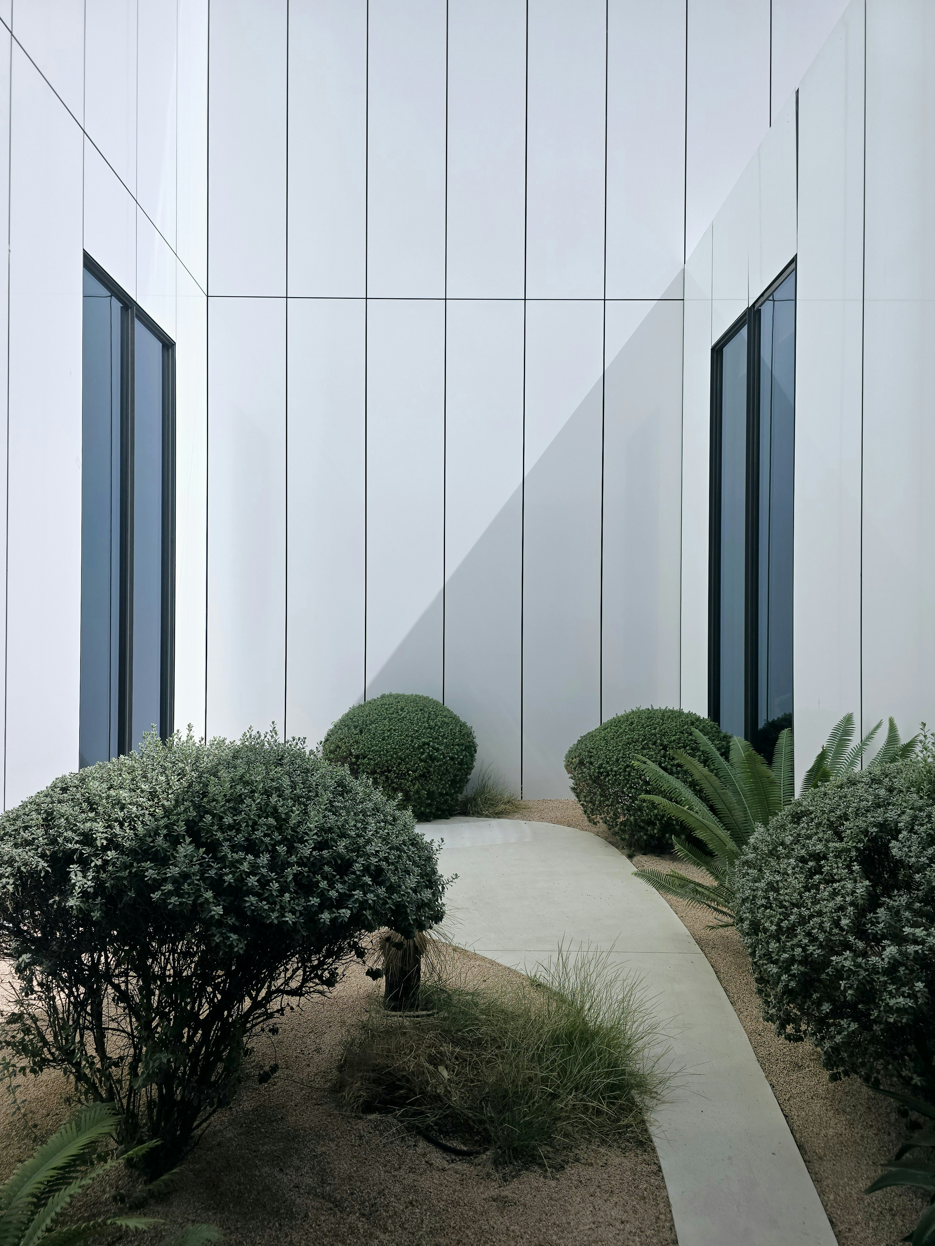 A pathway leads through a modern, enclosed garden. photo – Free ...