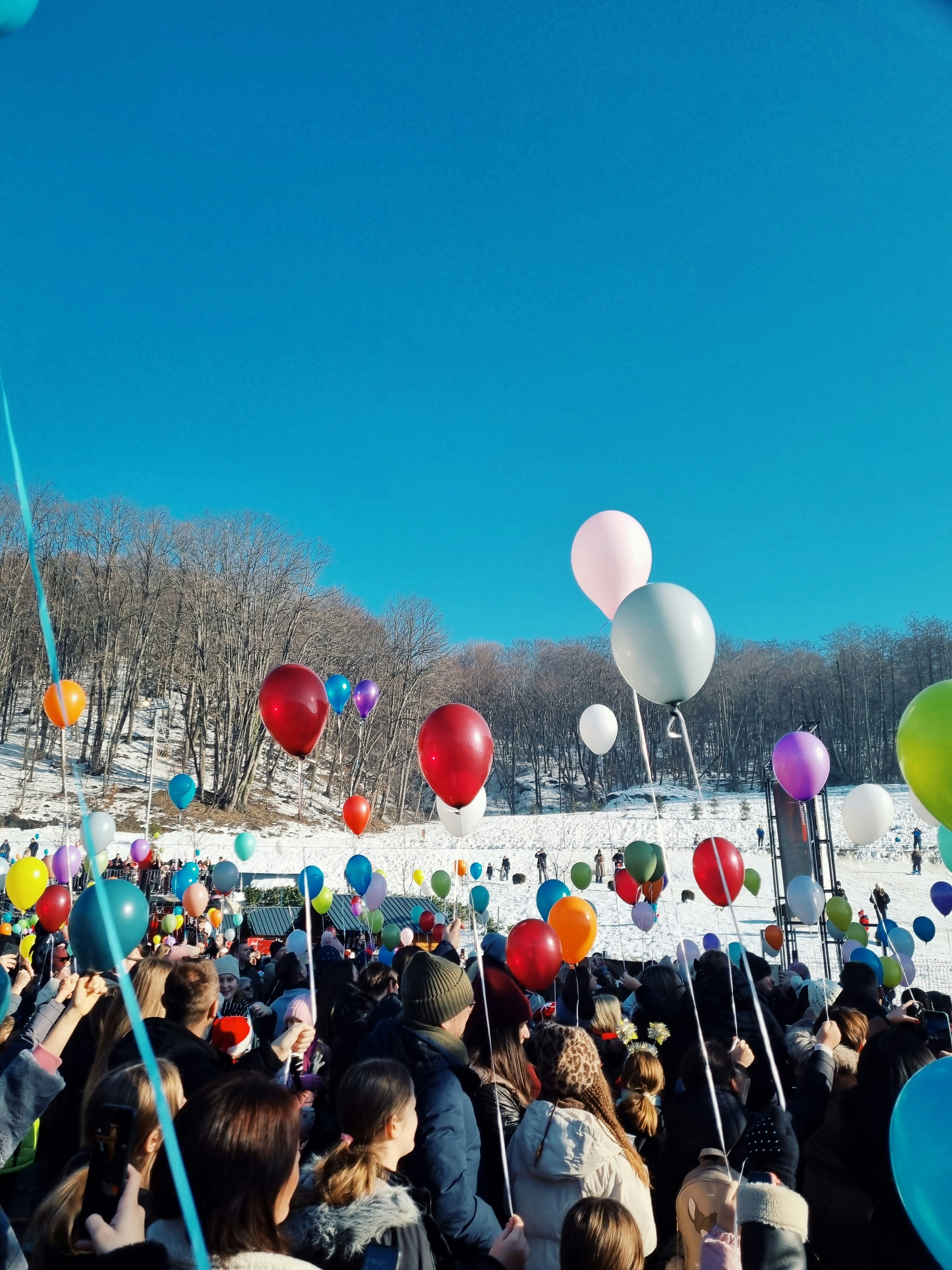 A crowd releases colorful balloons on a sunny day. photo – Free ...