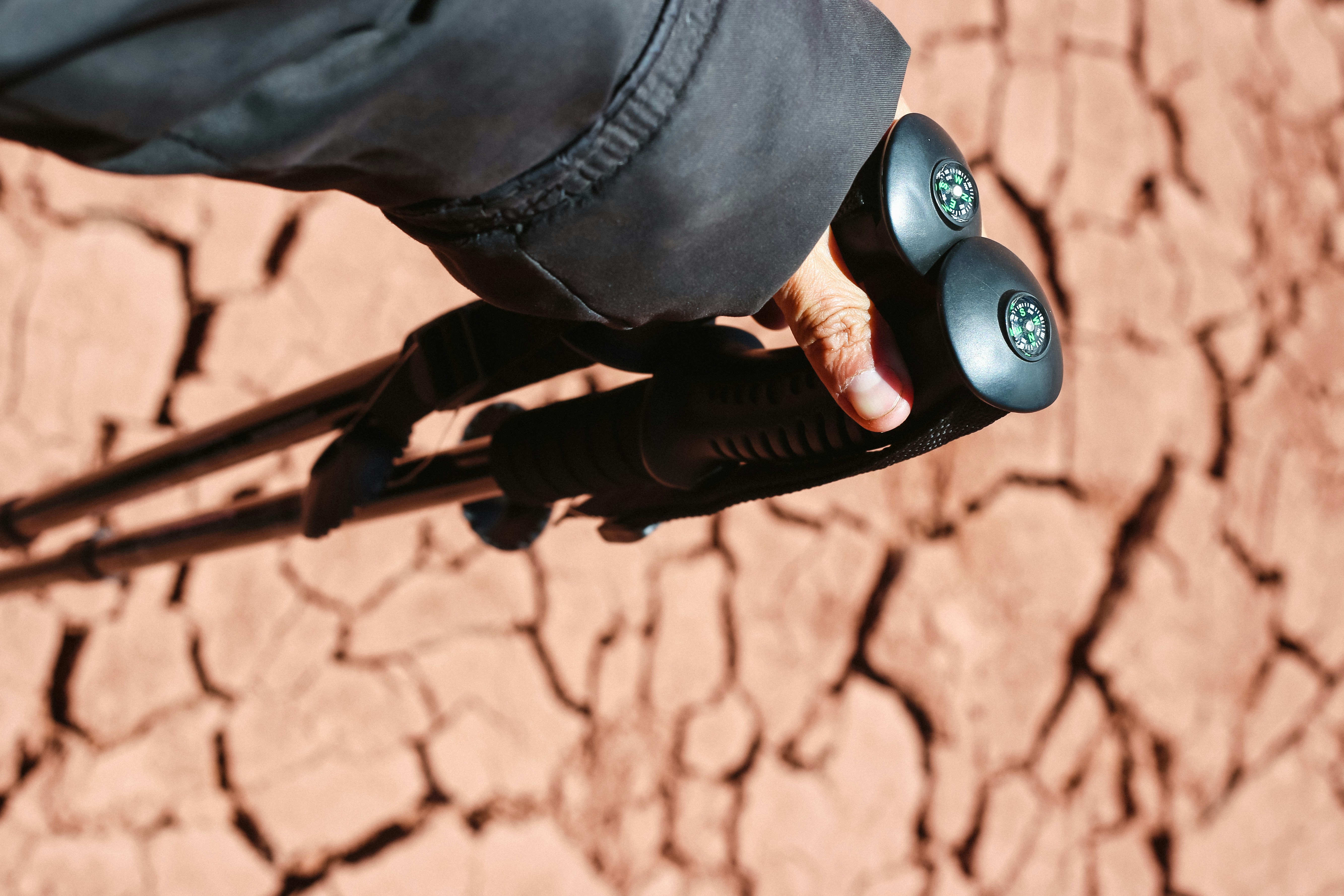 Crackling Grip: A Trekker’s Hand Clutches Trekking Poles Over Parched Earth