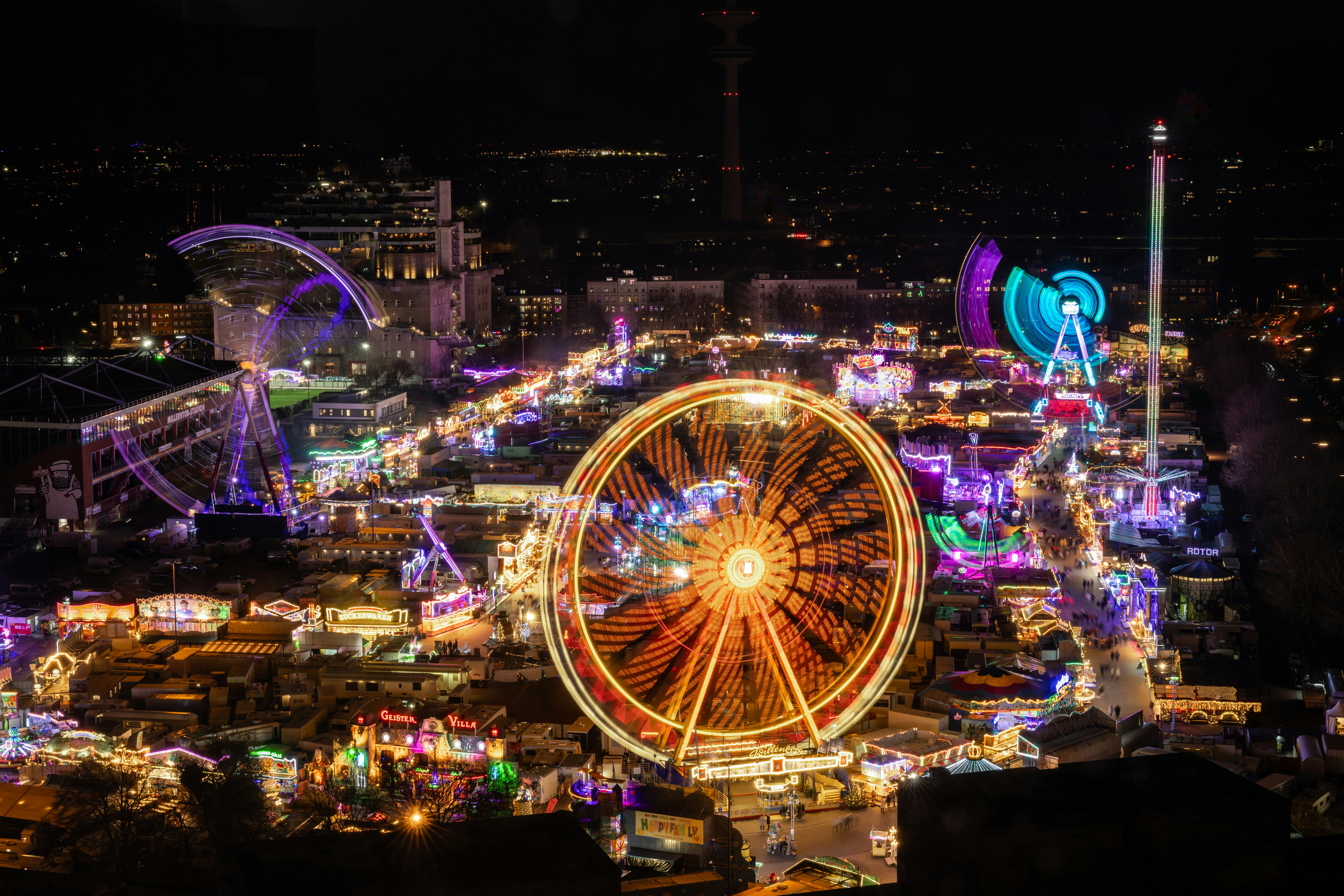 Une grande roue et un parc d’attractions brillent la nuit. photo ...
