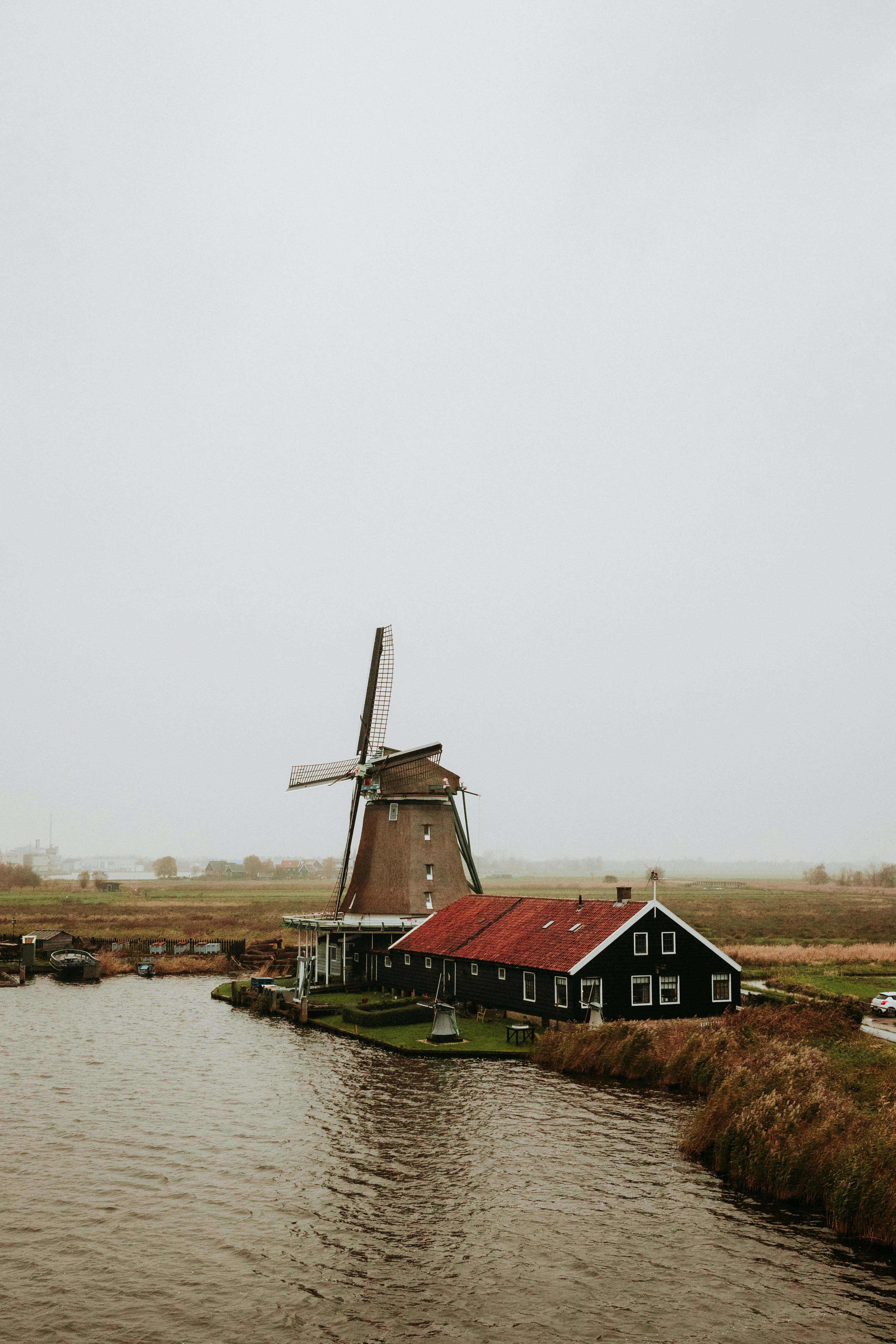 A windmill stands near a house by a river.Negley Stockman