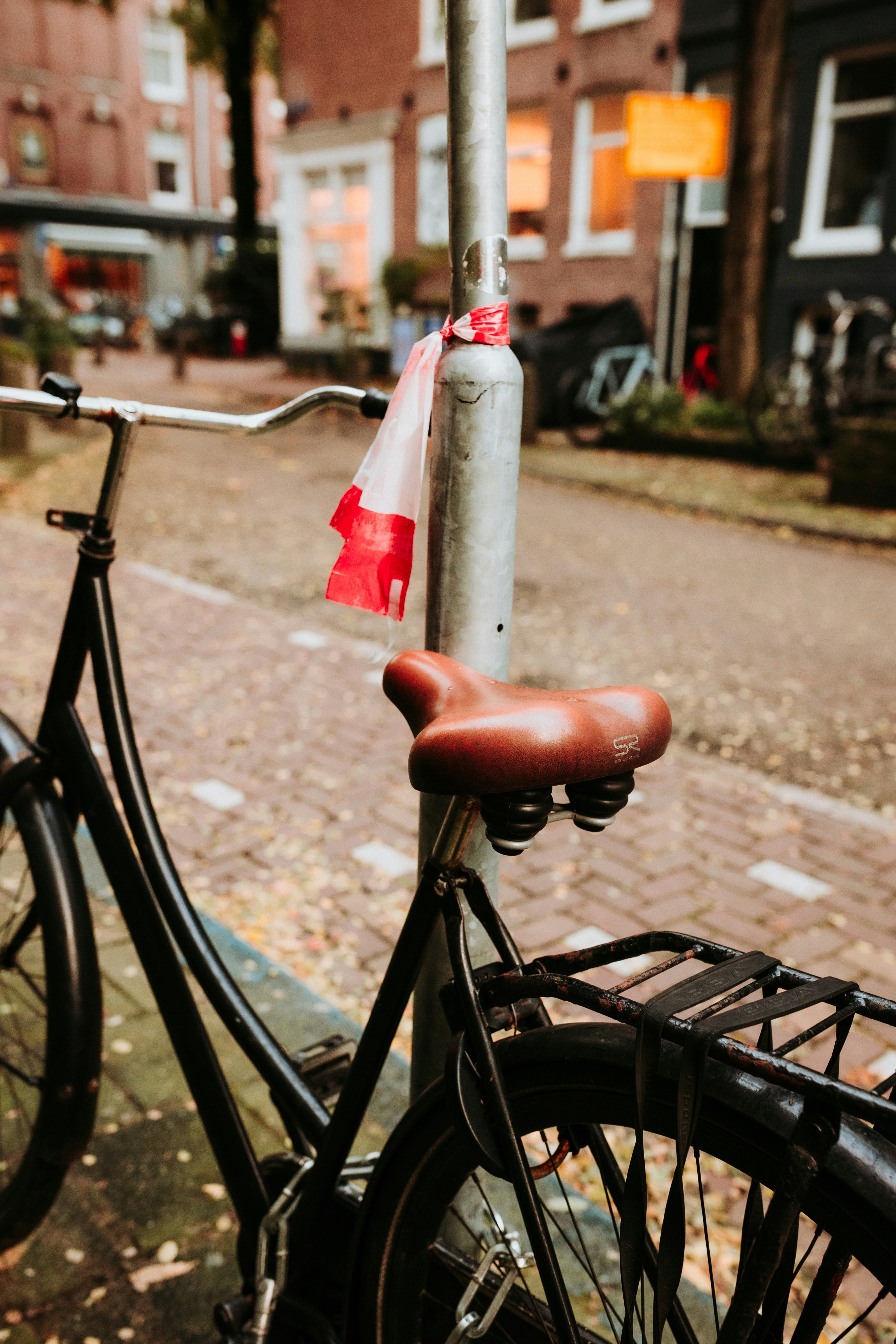 Red Ribbon on a Quiet Street: A City Bicycle Anchored to a Post