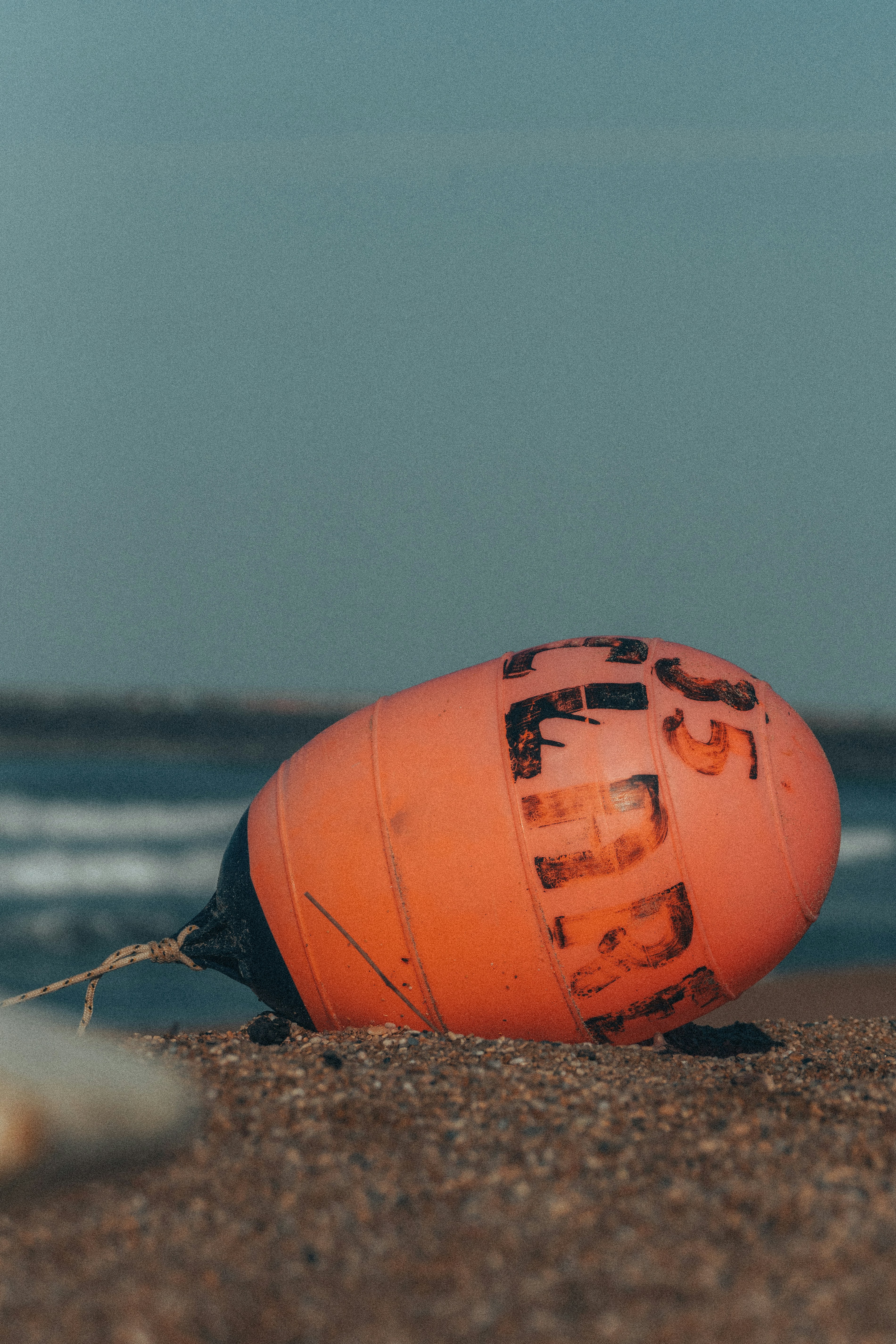 Orange Buoy on a Quiet Beach: Weathered Marker by the Sea