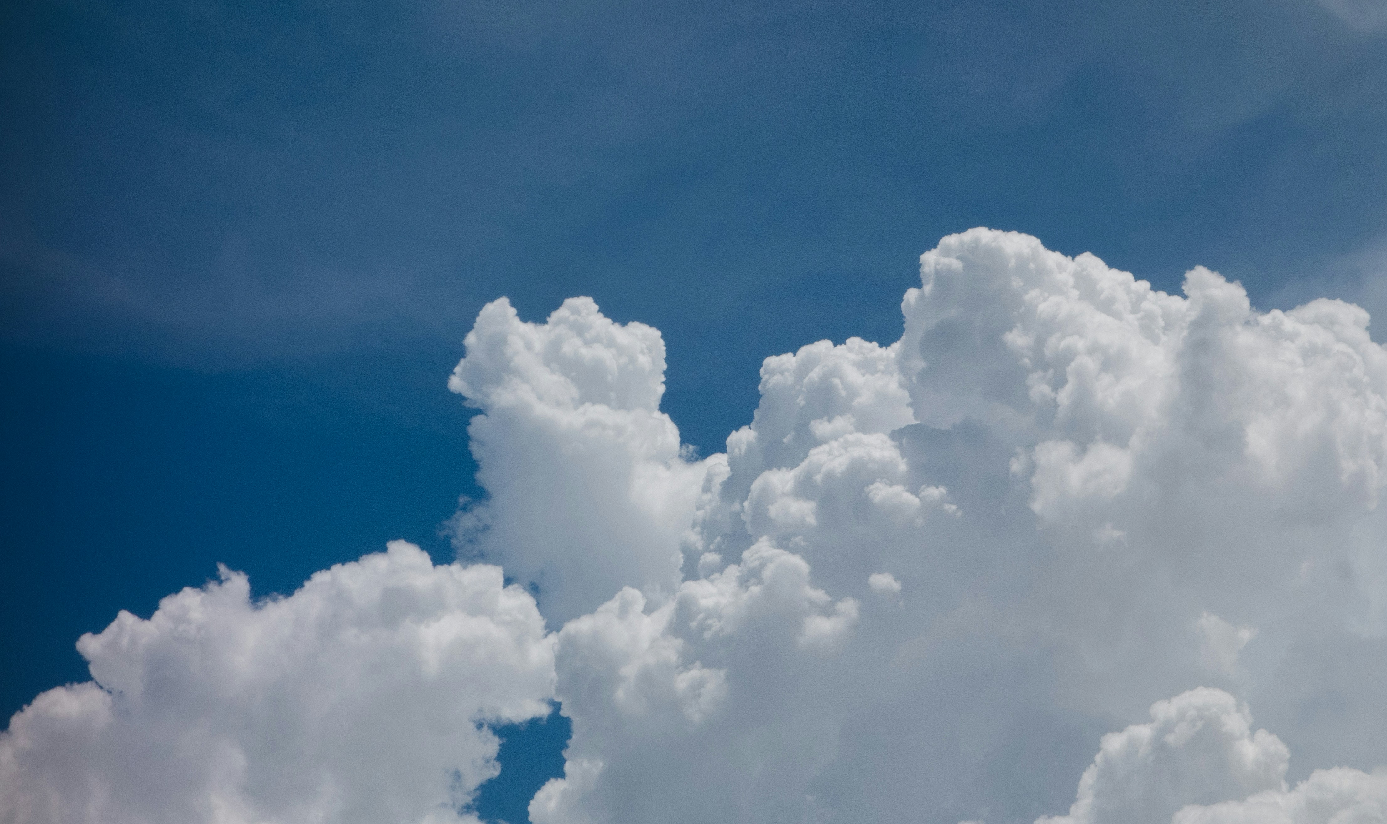 Billowing white clouds rise against a vivid blue sky.