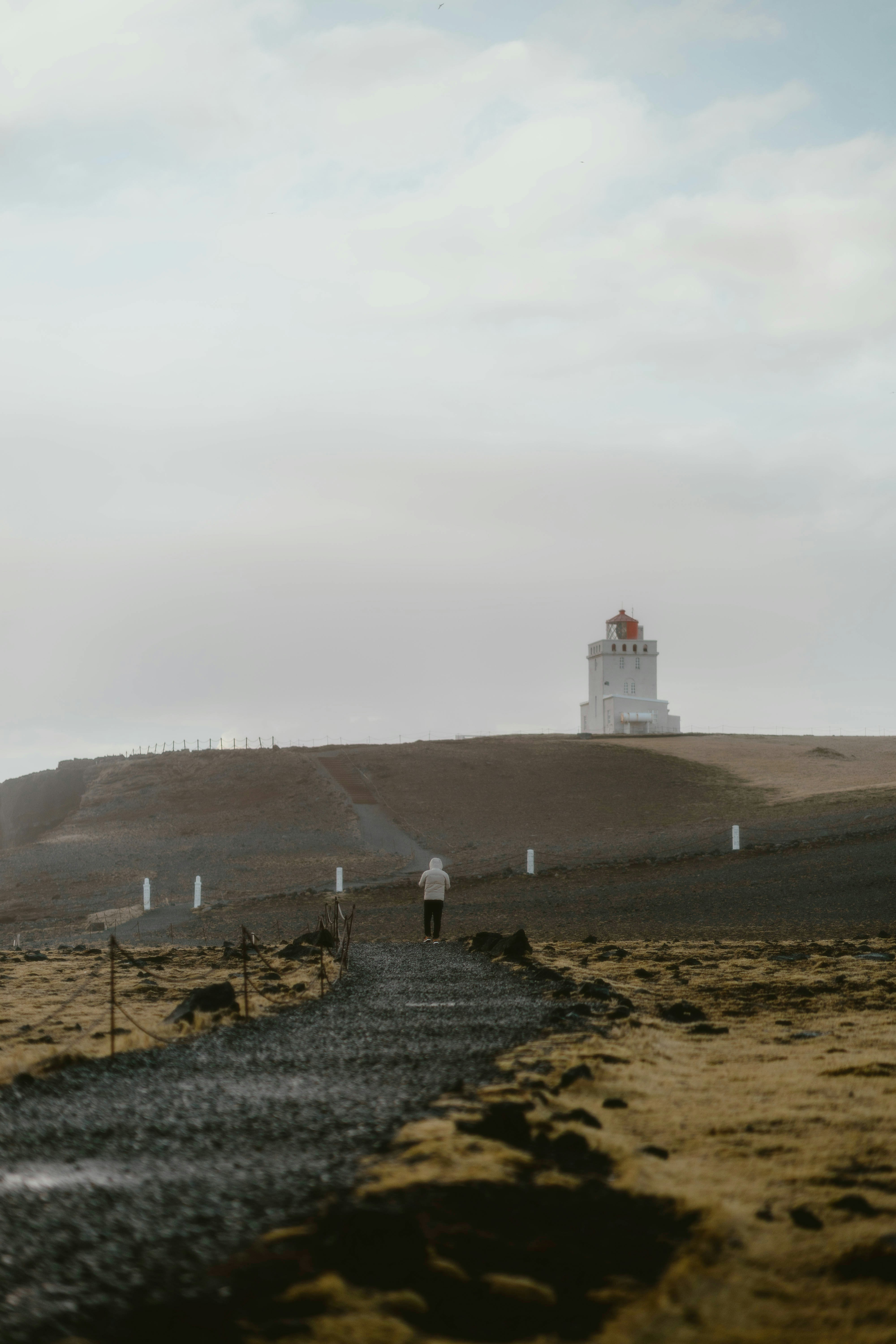 A person walks towards a lighthouse on a hill. photo – Free Human Image ...