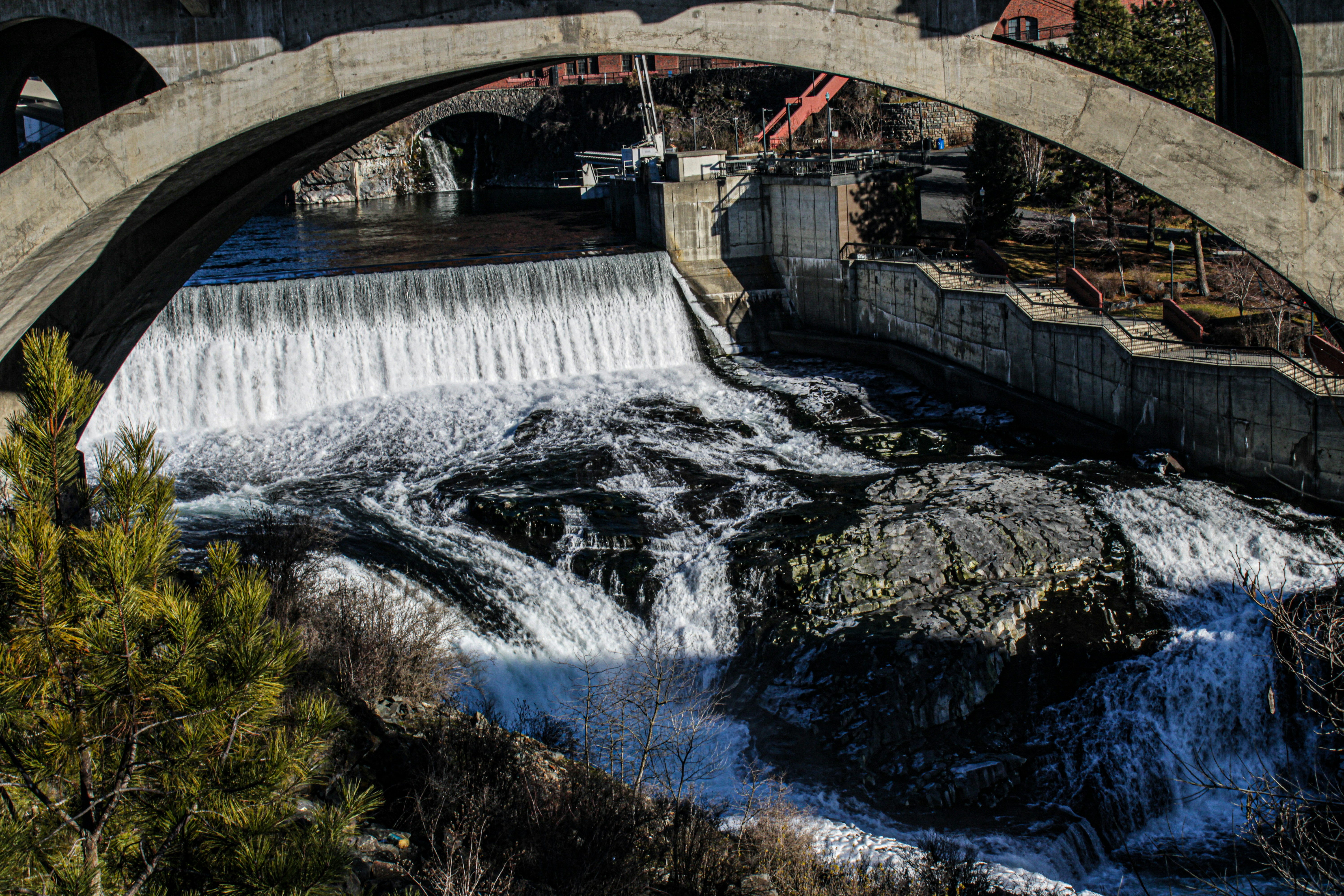 Water cascades over rocks and through a bridge arch. photo – Free ...