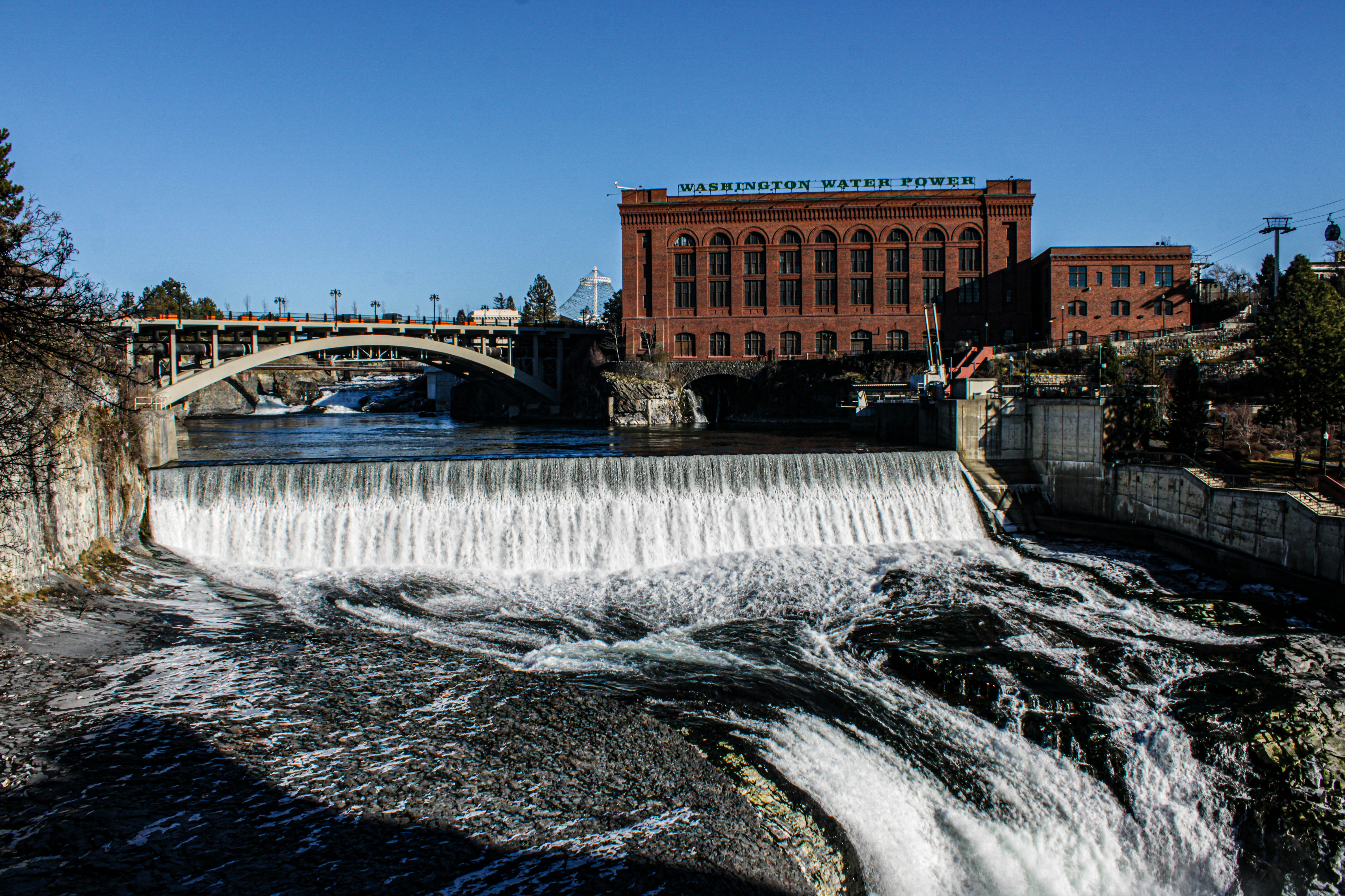 A scenic view of a waterfall and a brick building. photo – Free ...