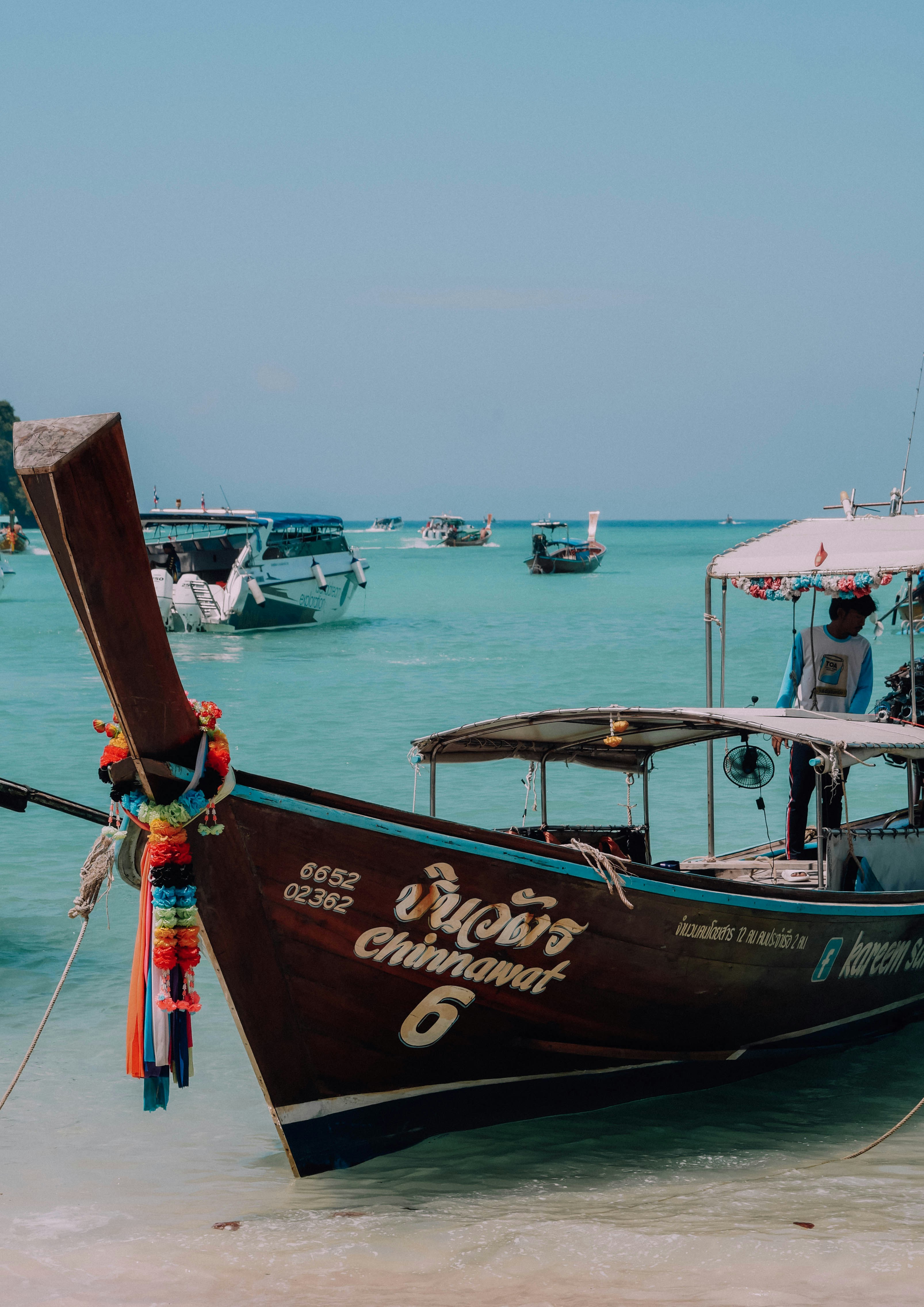 Rainbow Tassels at the Turquoise Shore: A Thai Long-Tail Boat in Calm Seas