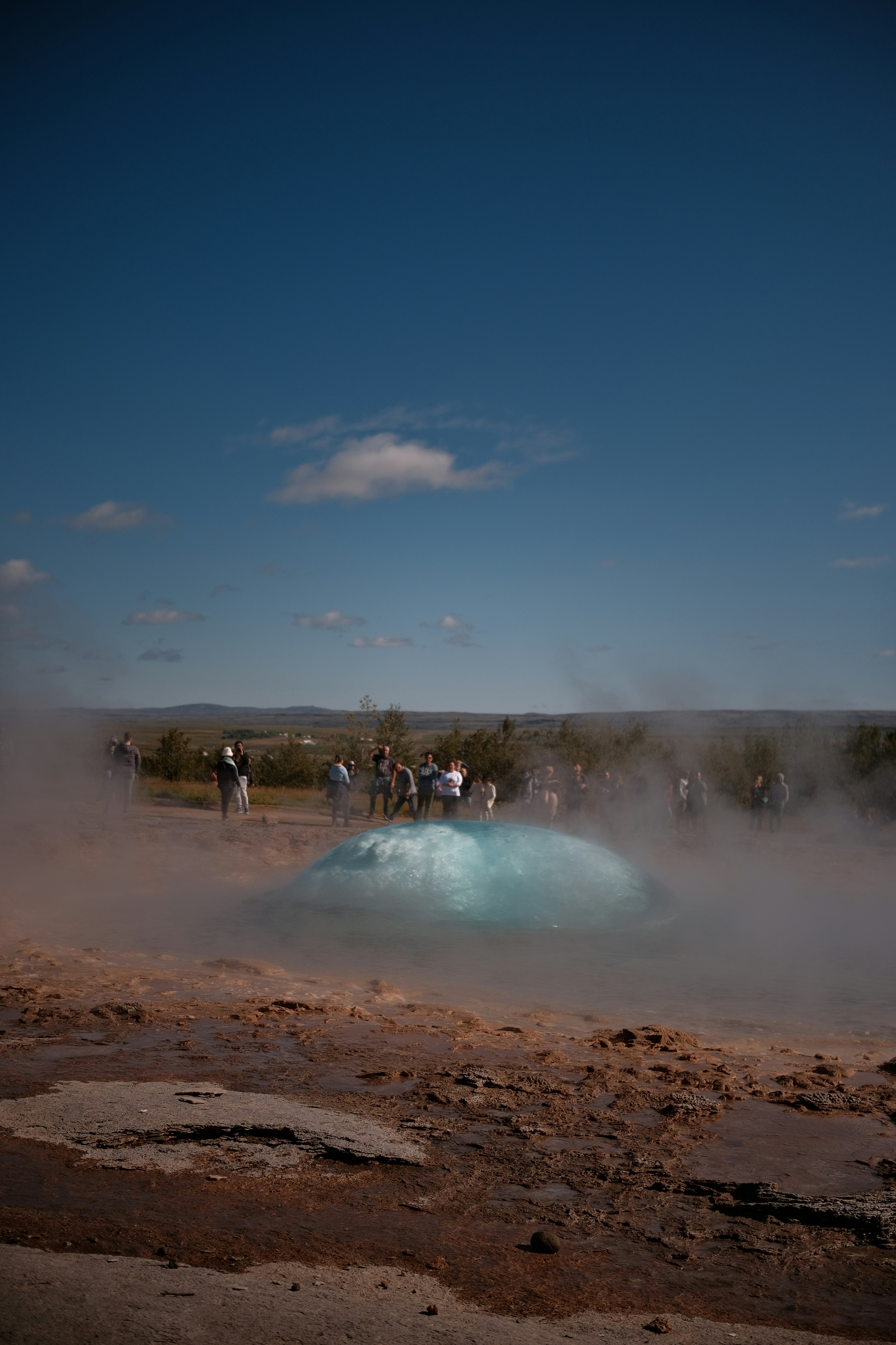 Azure Geyser Under a Steam Veil: Onlookers Observe a Desert Thermal Pool