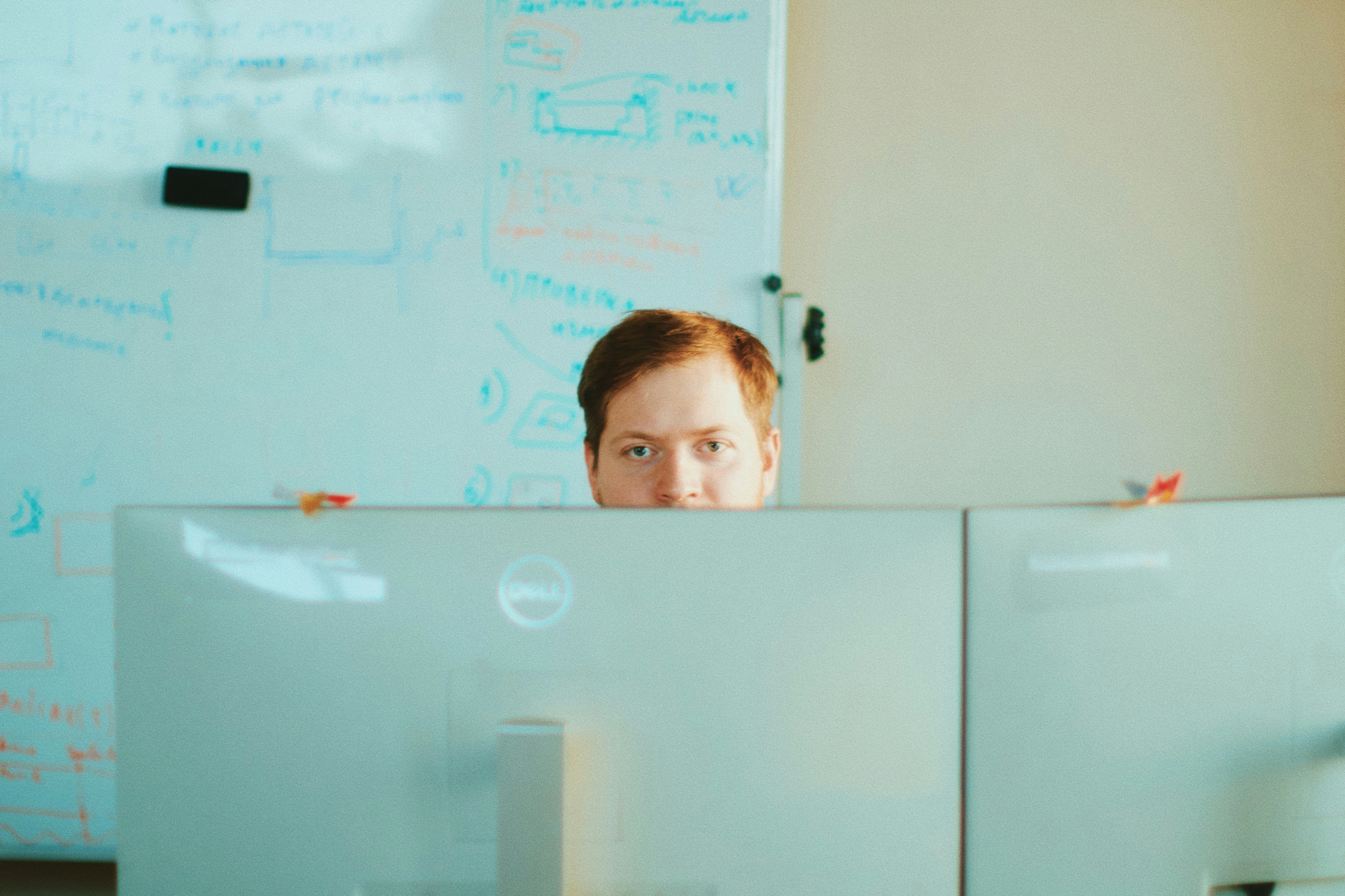 Man peers over the computer monitor in an office. photo – Free Man ...