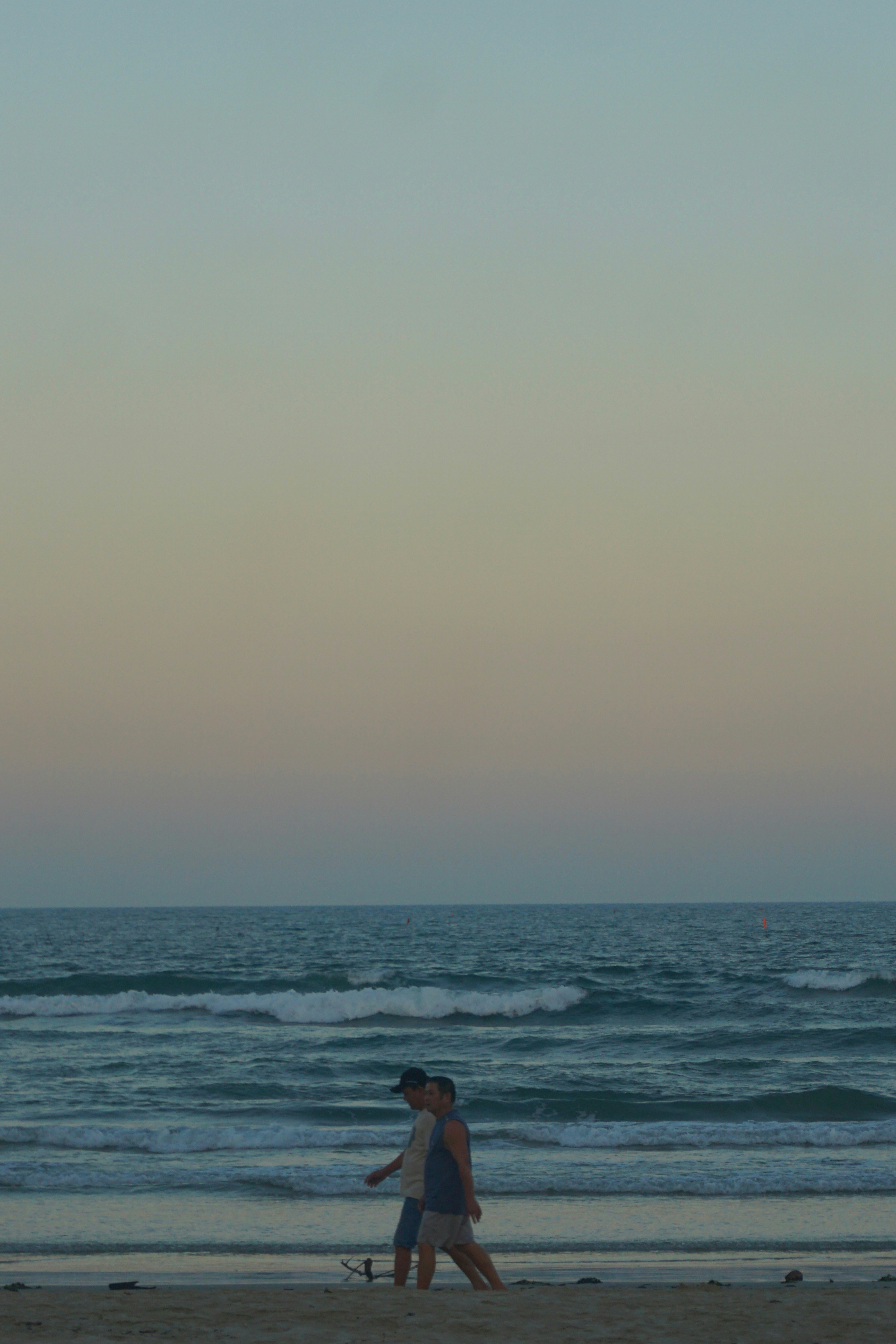 Pastel Shore Walk: Quiet silhouettes tracing the tide at dusk