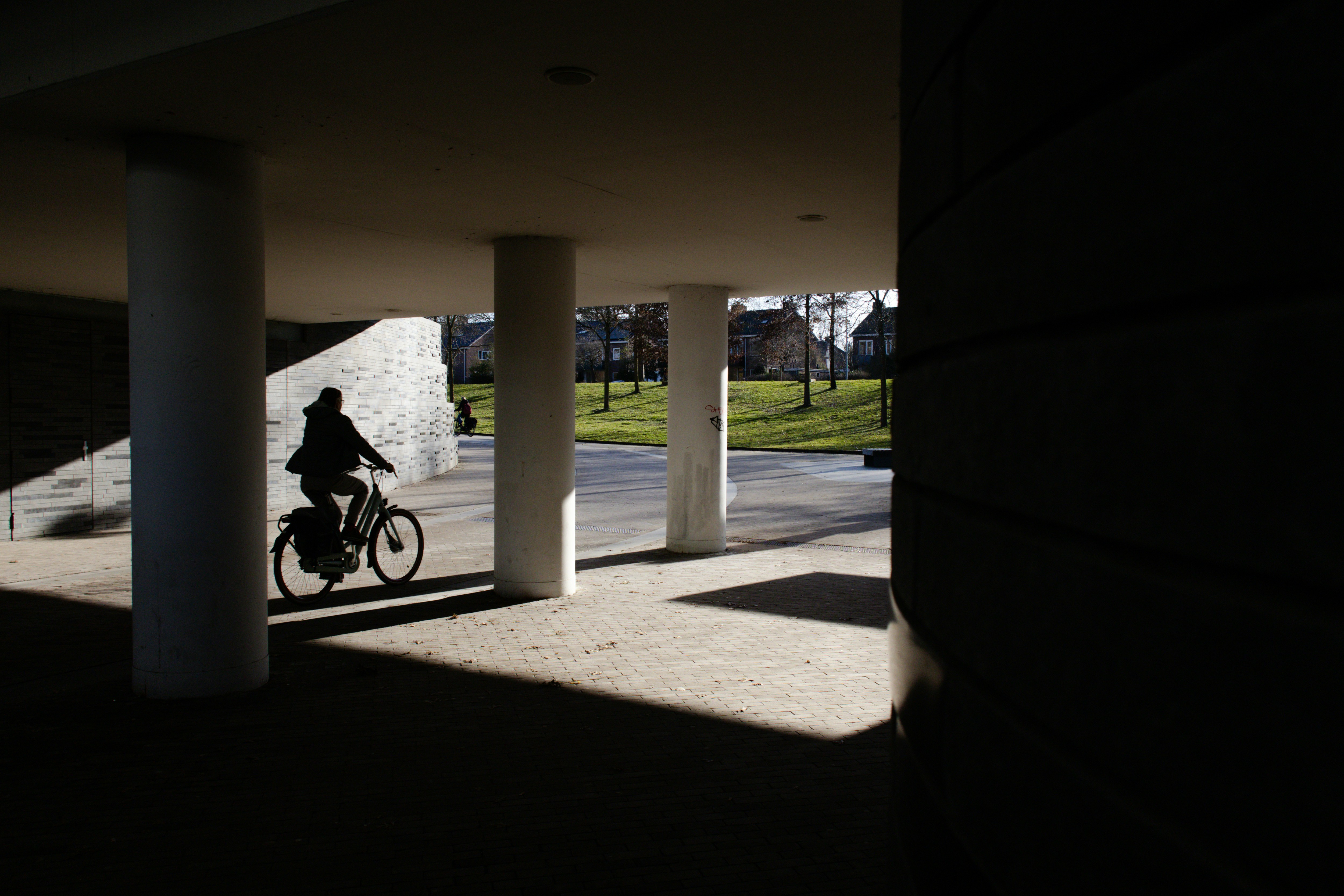 Arcade in Motion: A Cyclist Between Concrete Columns