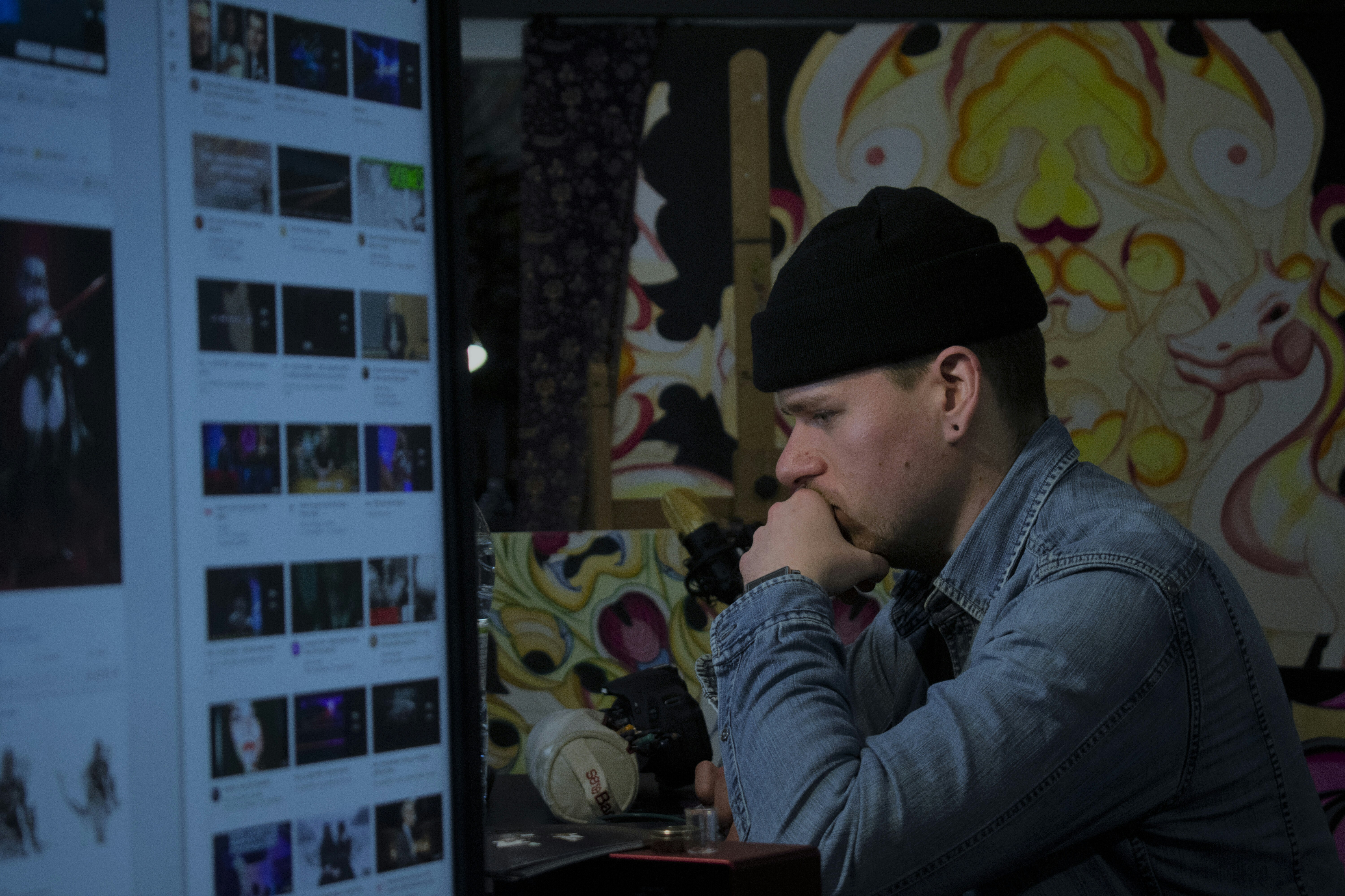 Person absorbed in viewing digital content on a screen, surrounded by vibrant artwork.