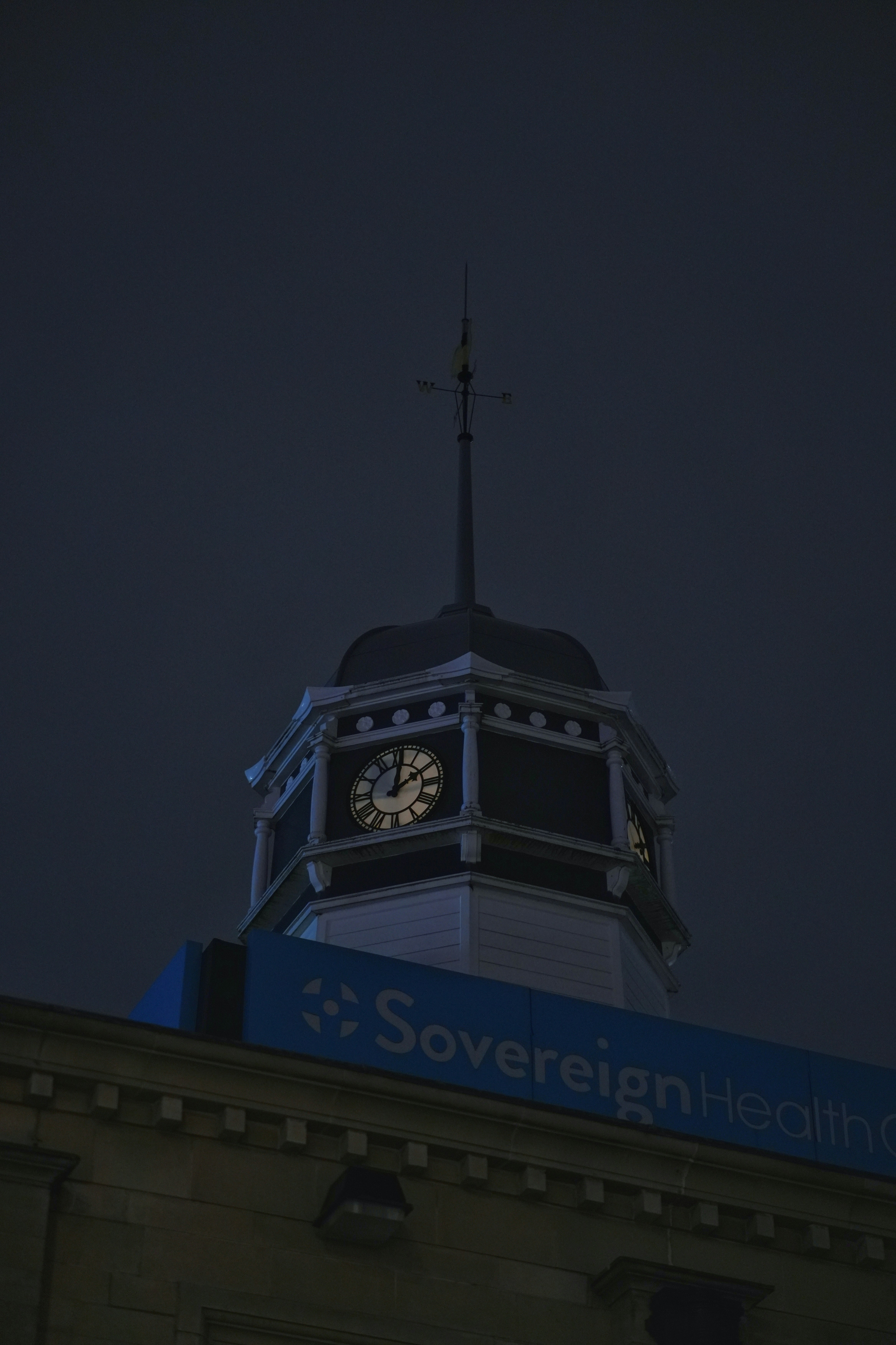 Clock tower atop a building at night.