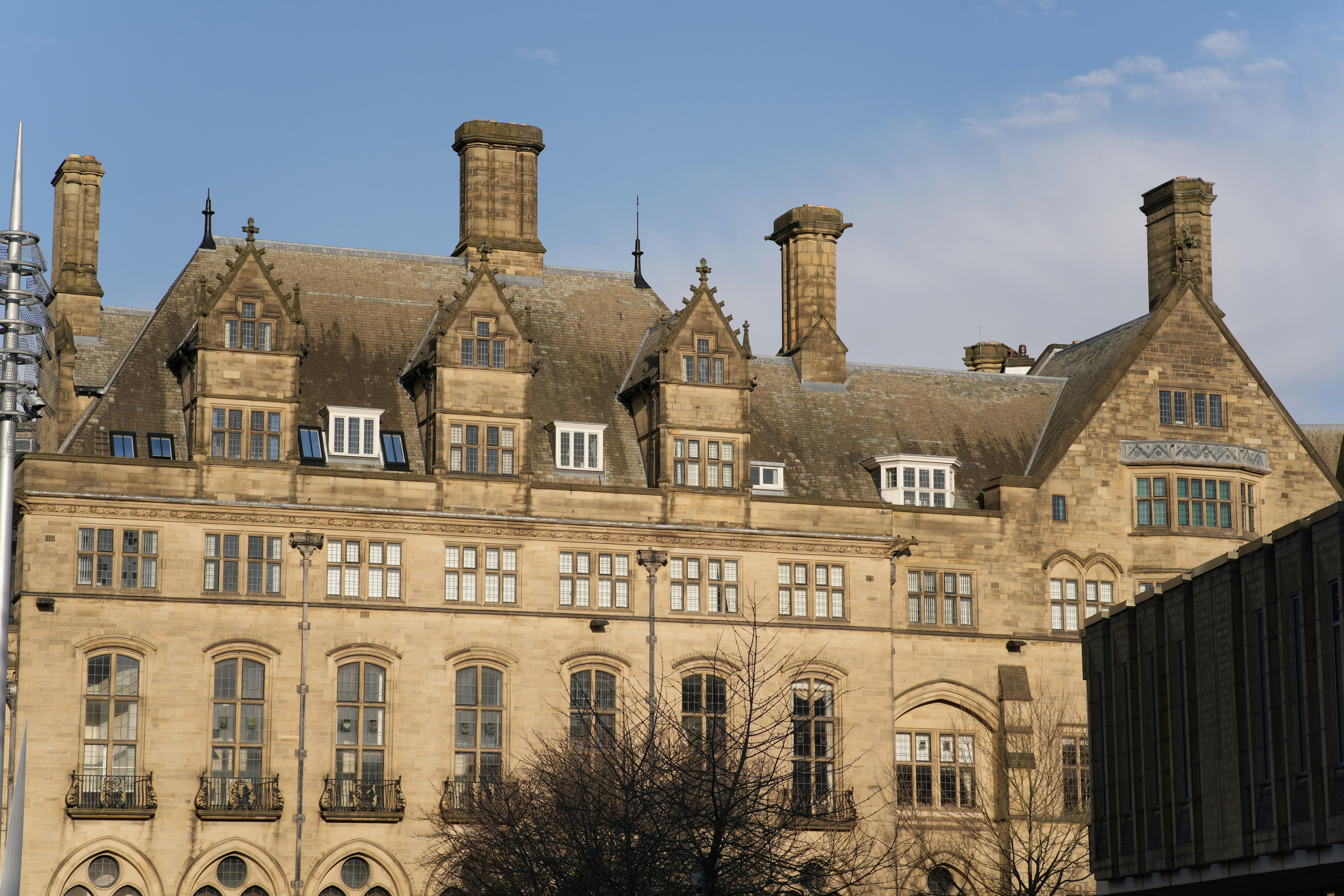 Victorian-era building with ornate stonework and multiple chimneys under a blue sky.