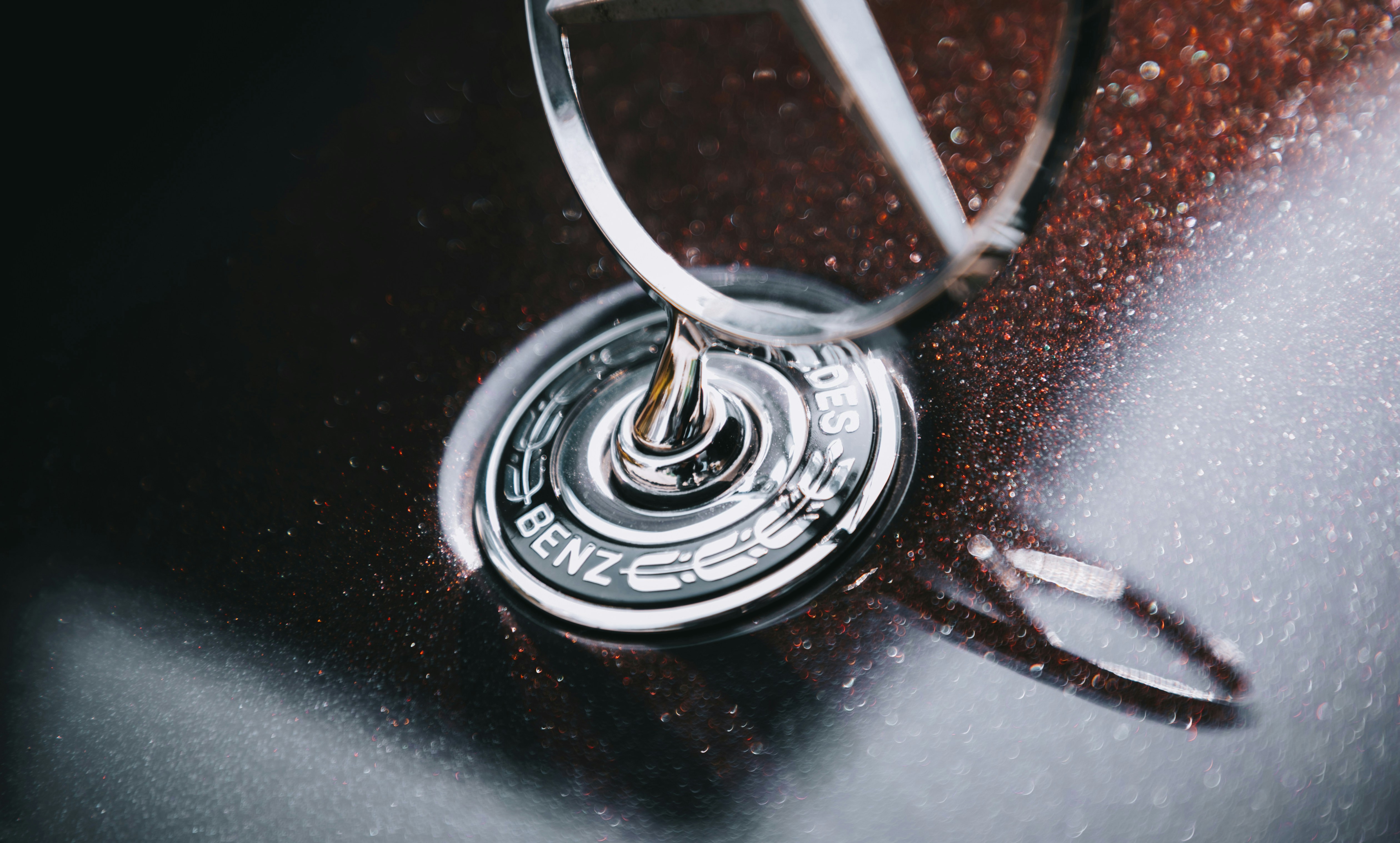 Haloed Chrome Over Scarlet: Mercedes-Benz Emblem in Macro Detail