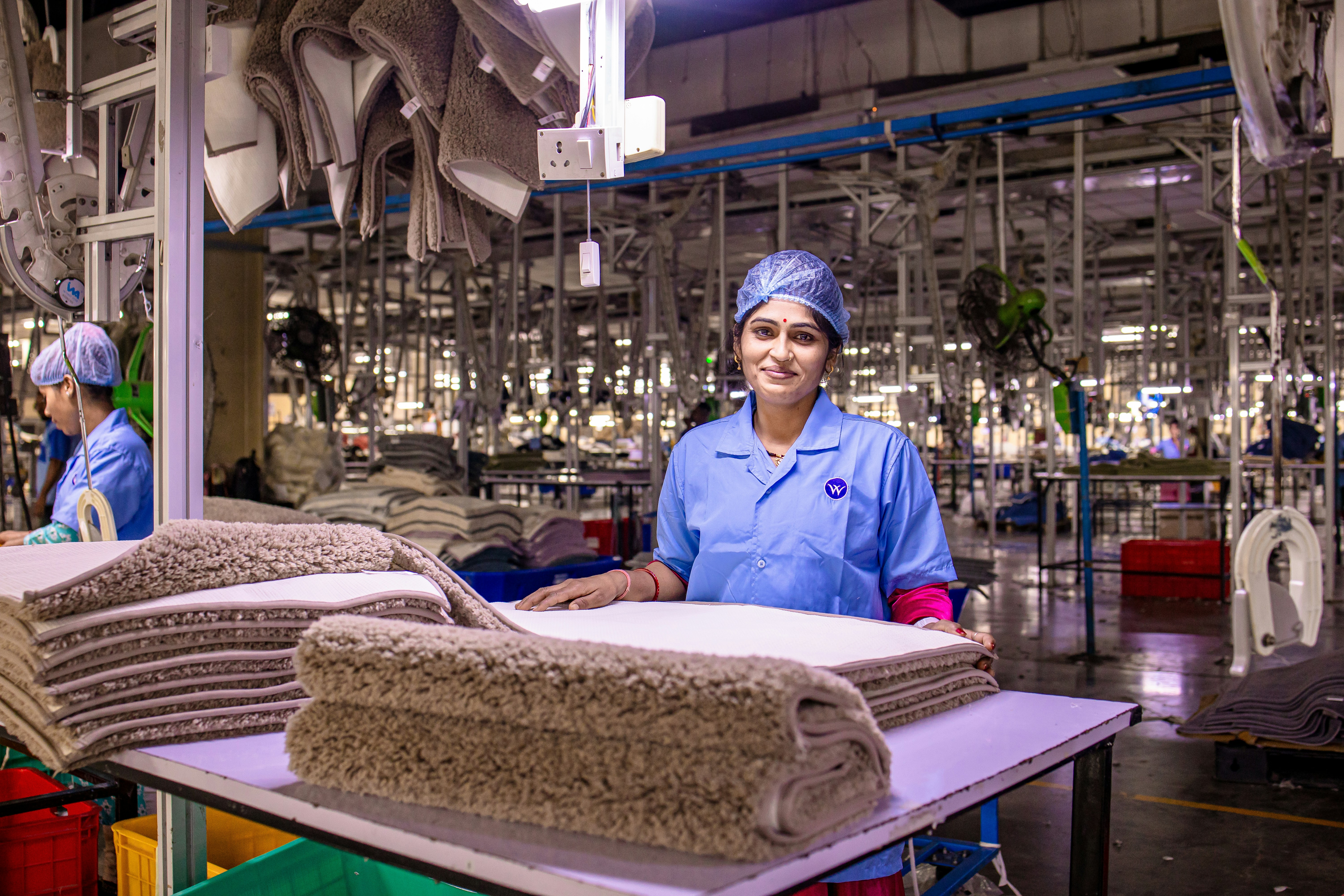 A worker in a factory smiles at the camera. photo – Free Worker Image ...