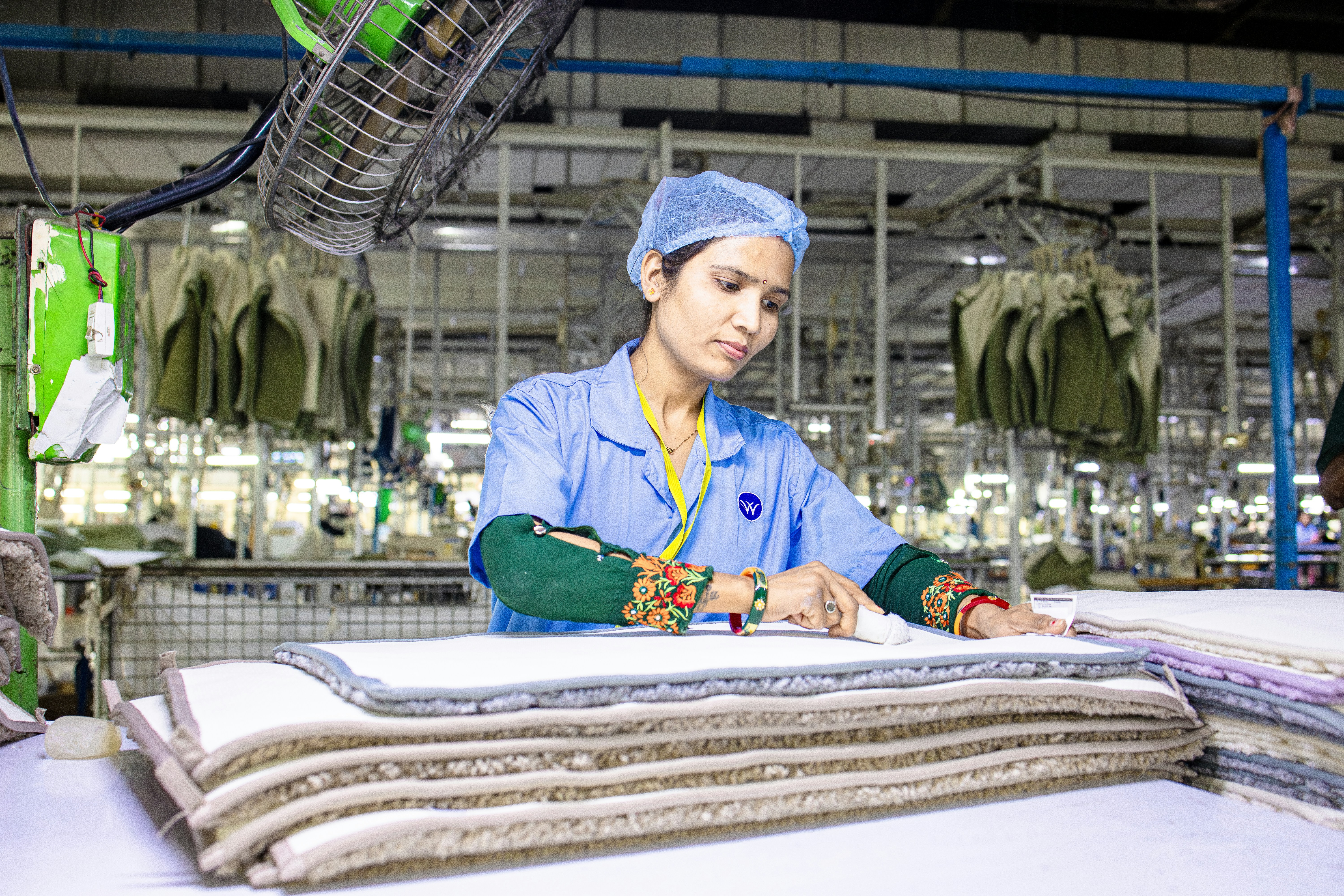 A factory worker is inspecting stacks of textiles. photo – Free Worker ...