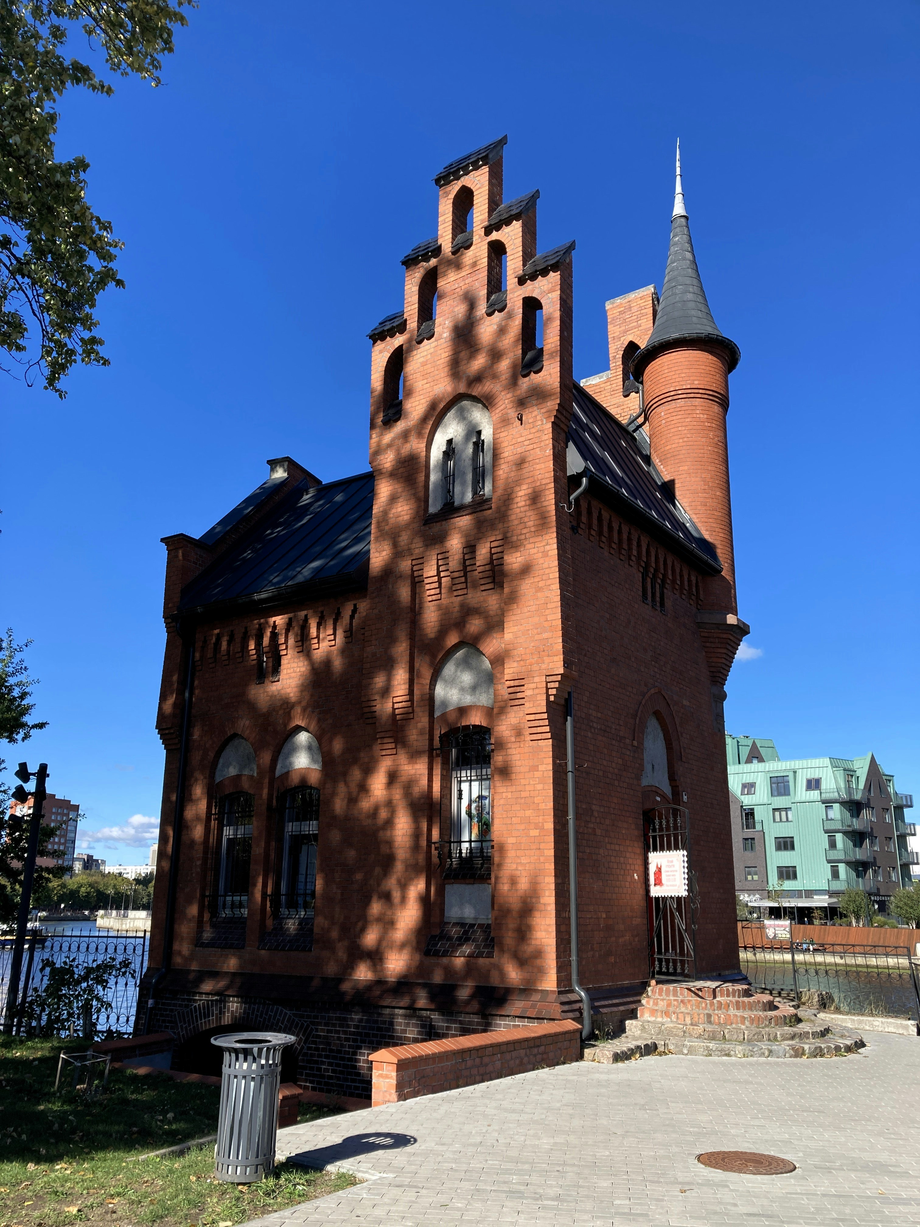 Sunlit Brick Gothic House with a Turret by the River