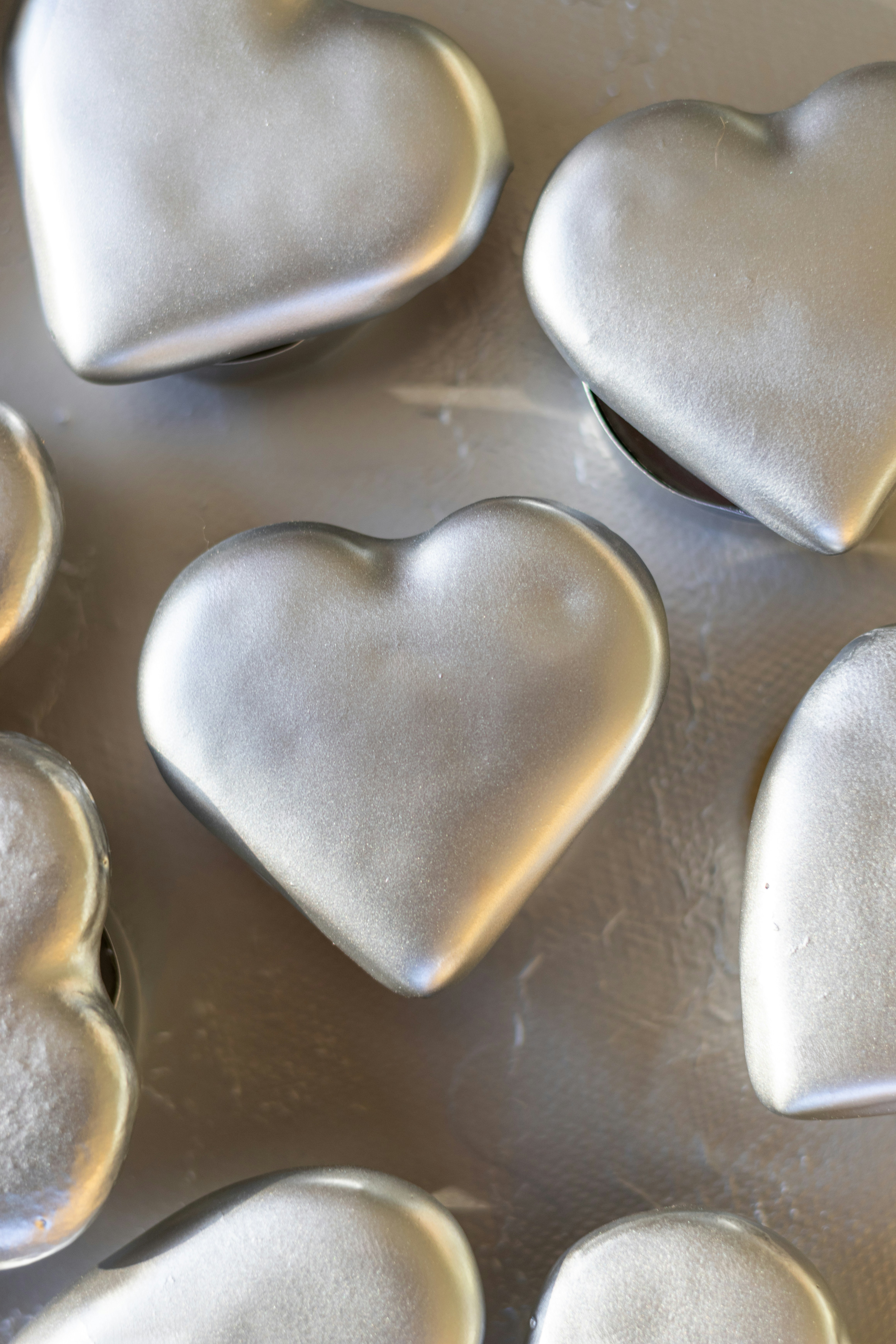 Silver heart-shaped molds are arranged on a surface. photo – Free Love ...